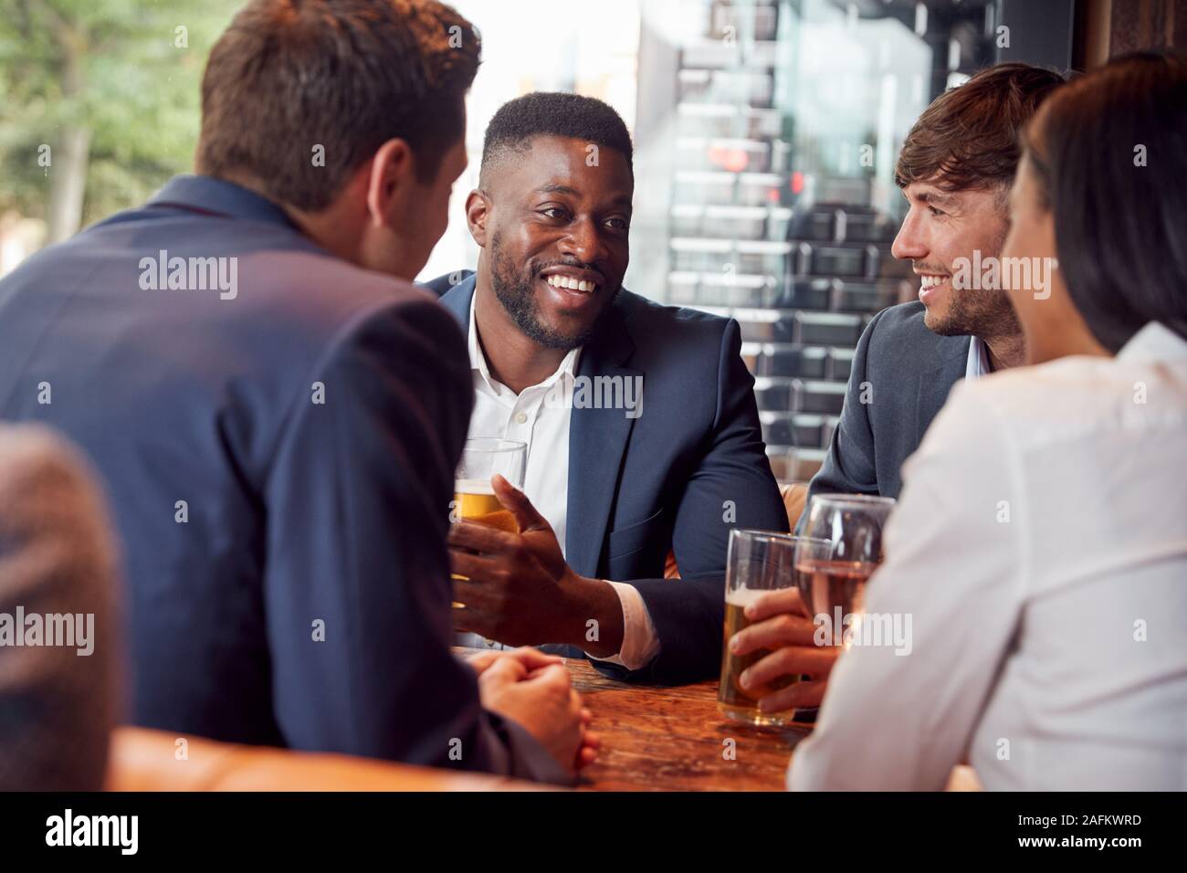 Group Of Business Colleagues Meeting For Drinks And Socializing In Bar ...