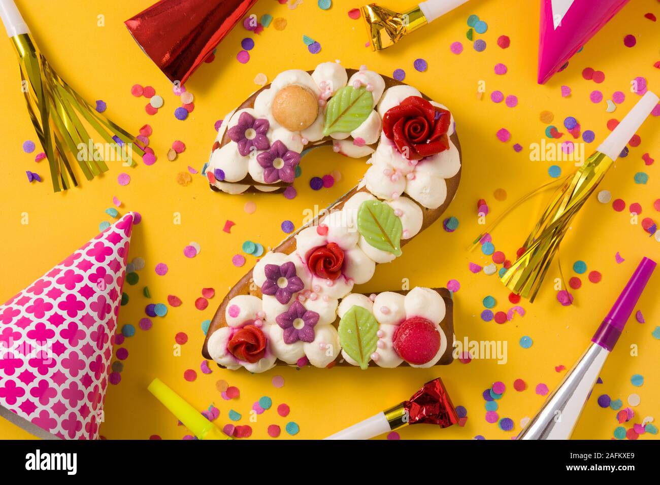 Number two cake decorated with flowers, macarons and confetti isolated ...