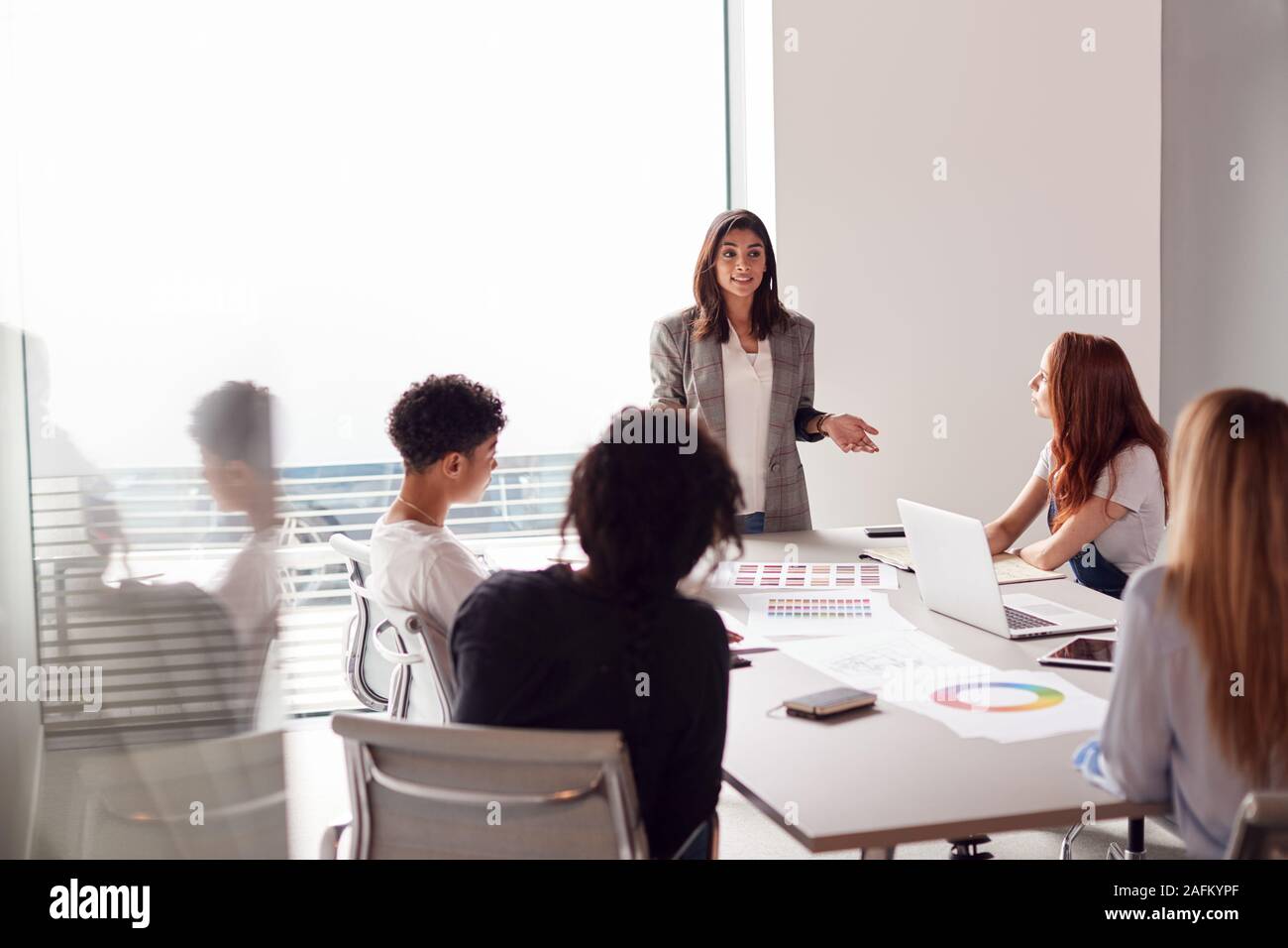 Female Boss Gives Presentation To Team Of Young Businesswomen Meeting ...