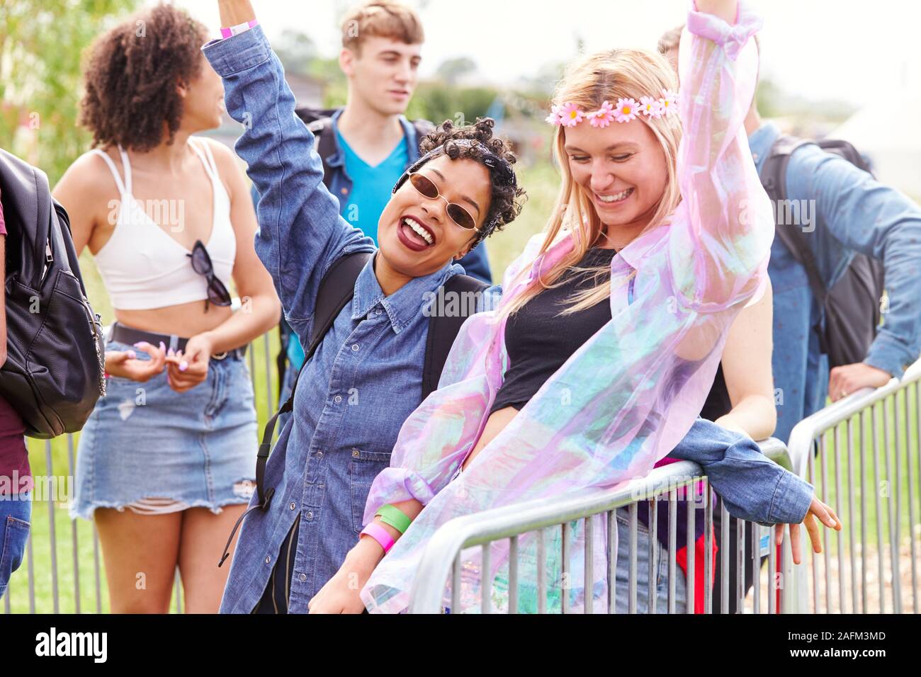 Portrait Of Female Friends Waiting Behind Barrier At Entrance To Music ...