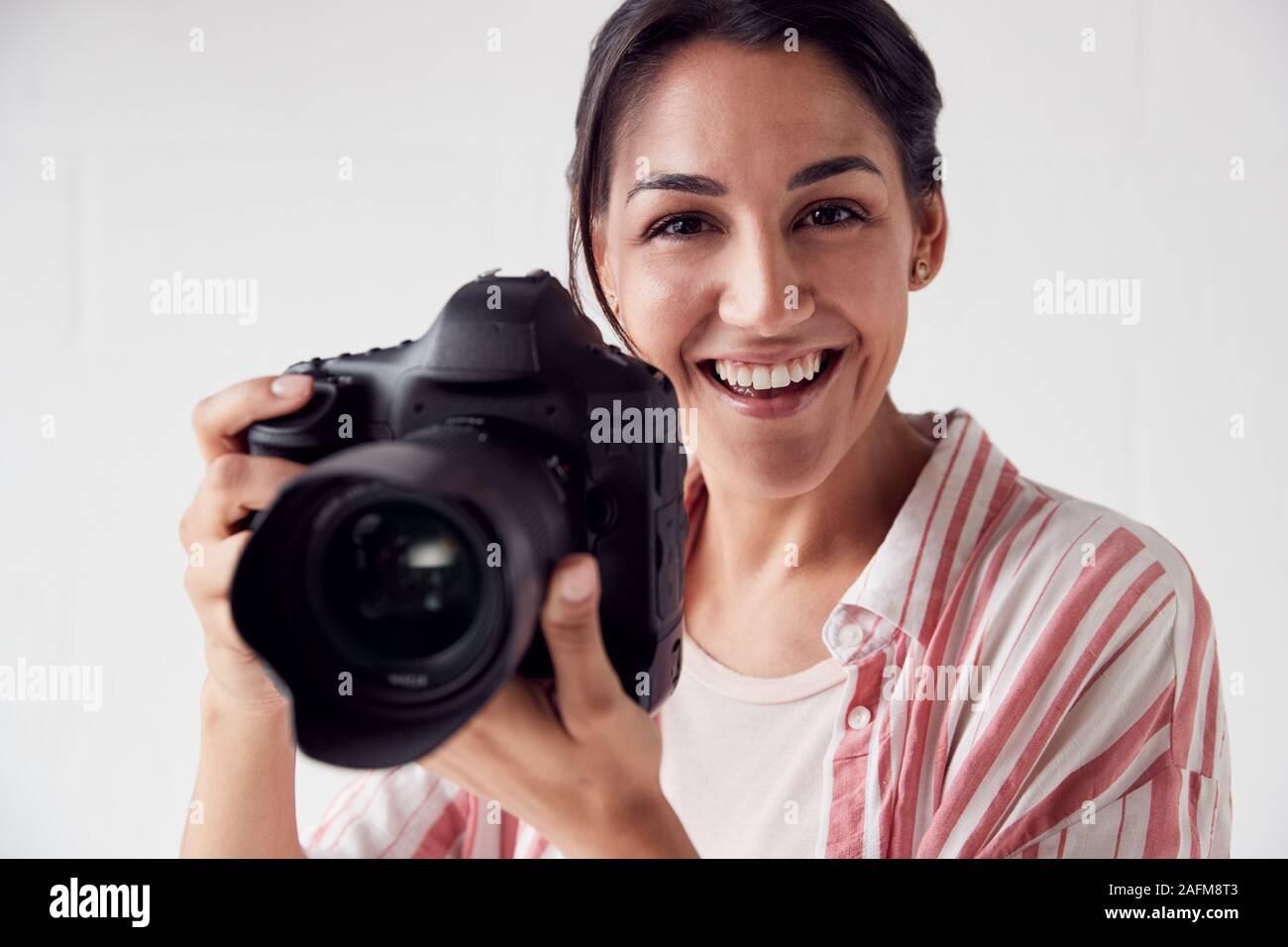 Portrait Of Smiling Female Photographer With Camera Against White ...