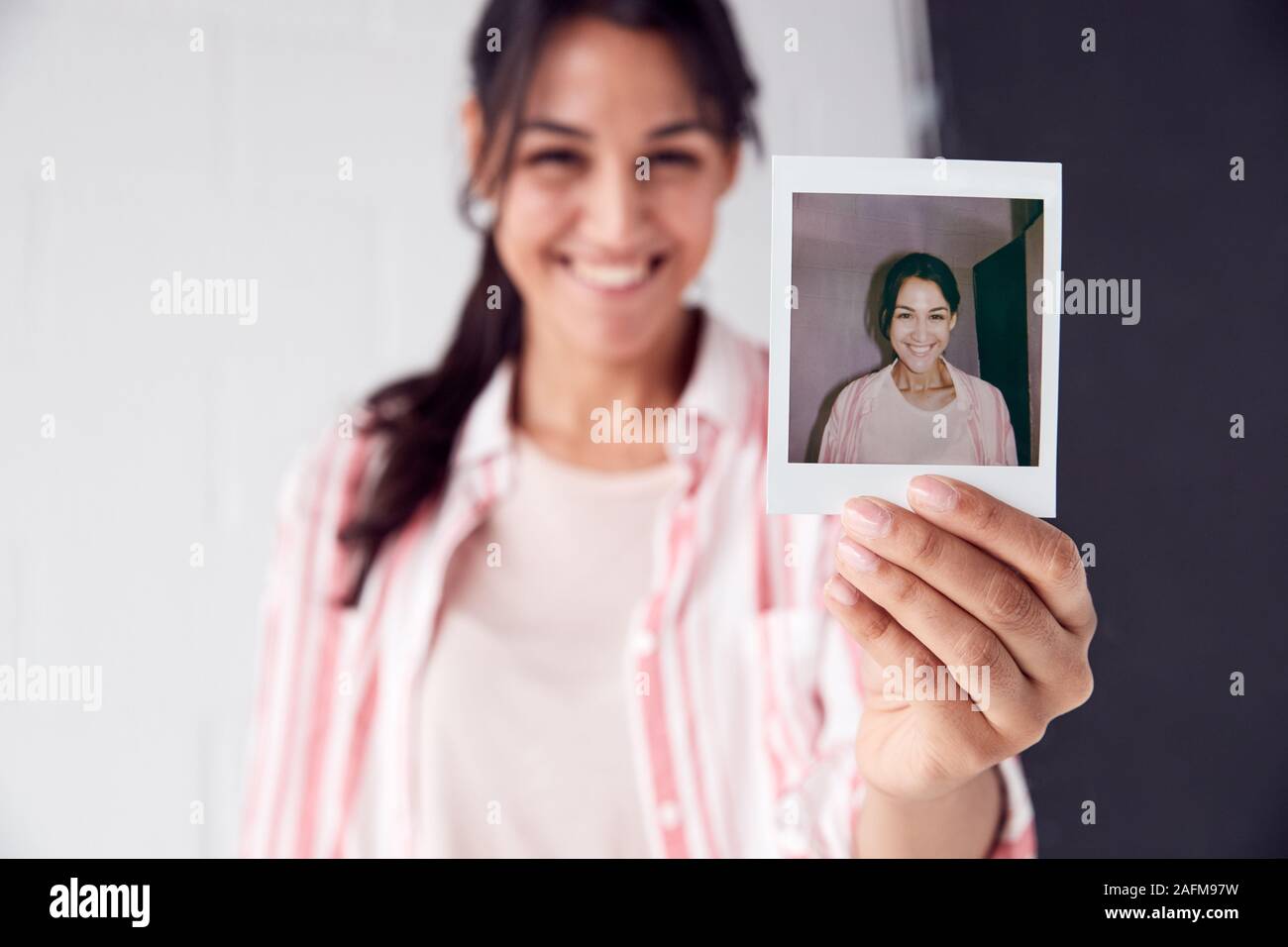 Portrait Of Female Photographer On Photo Shoot Holding Up Instant