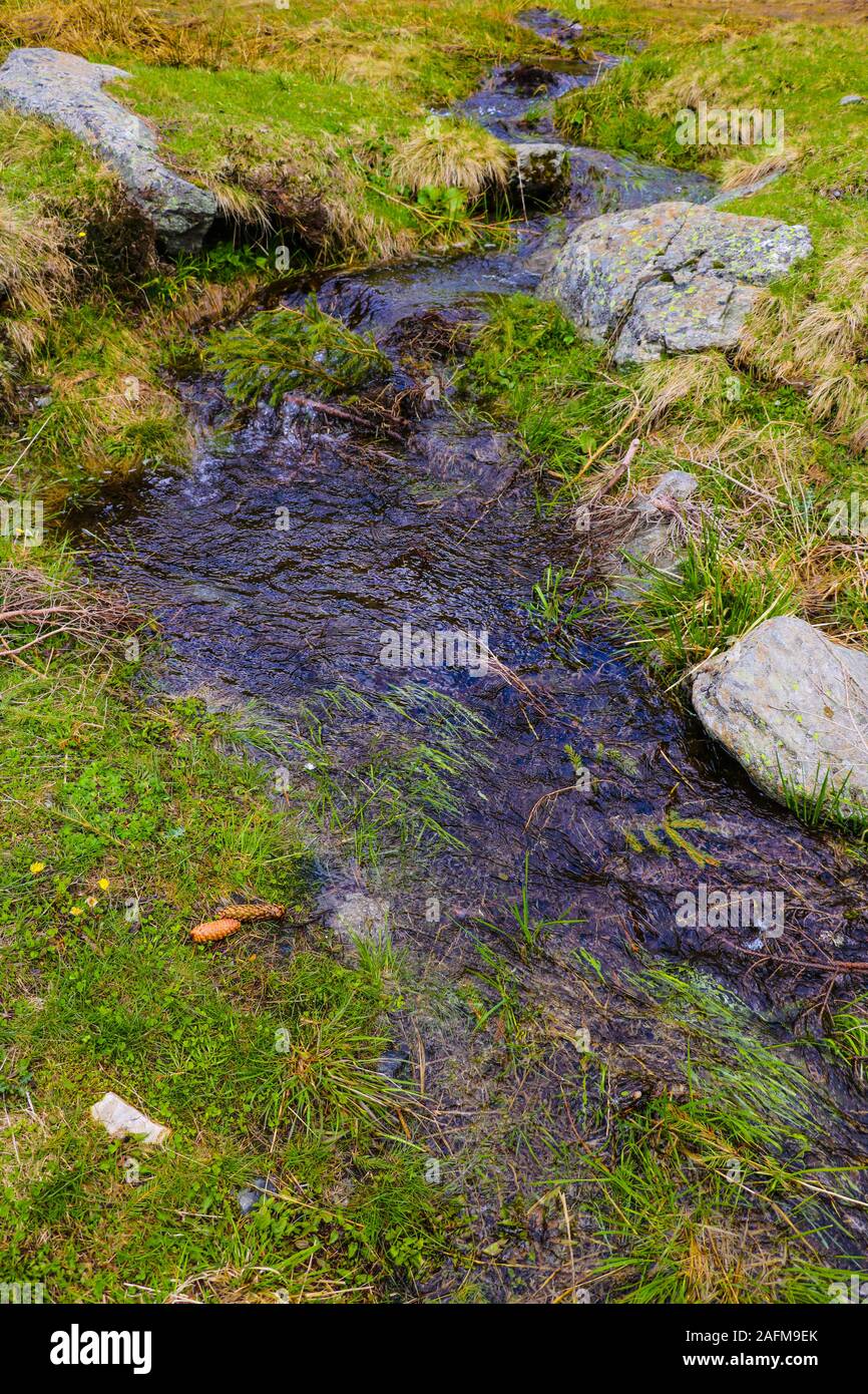 Mountain stream flows along the mountainside, snow. Nature background ...