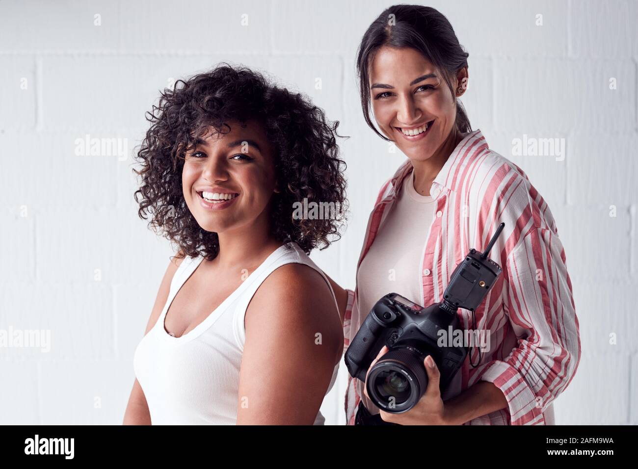 Portrait Of Smiling Female Photographer Holding Camera With Model In ...