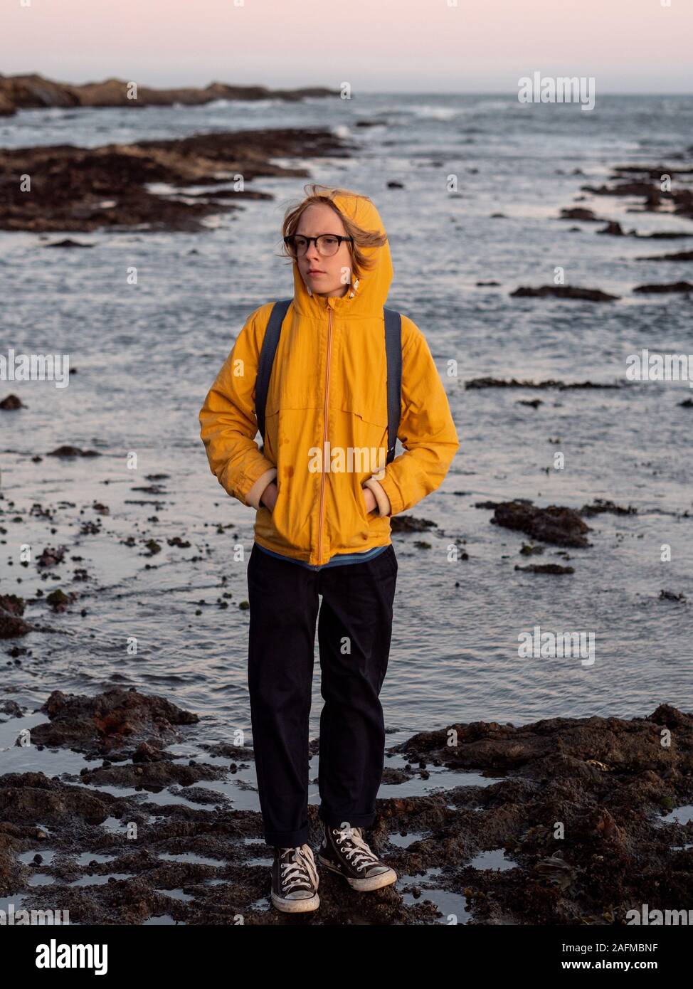 Full body portrait of tween standing on rocky shore at sunset Stock ...