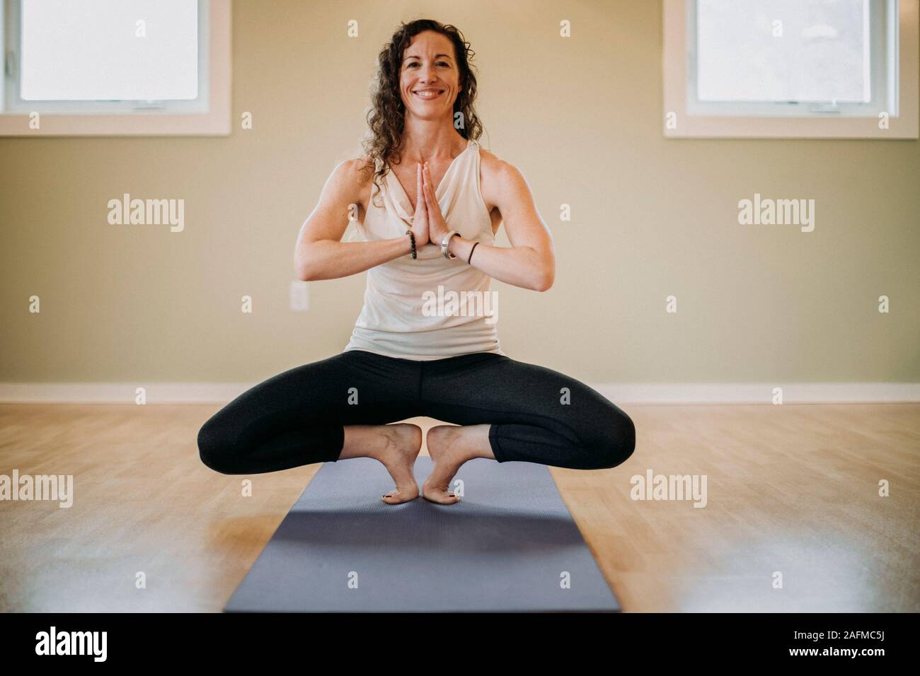 smiling woman balancing on her toes on a yoga in an indoor studio Stock ...