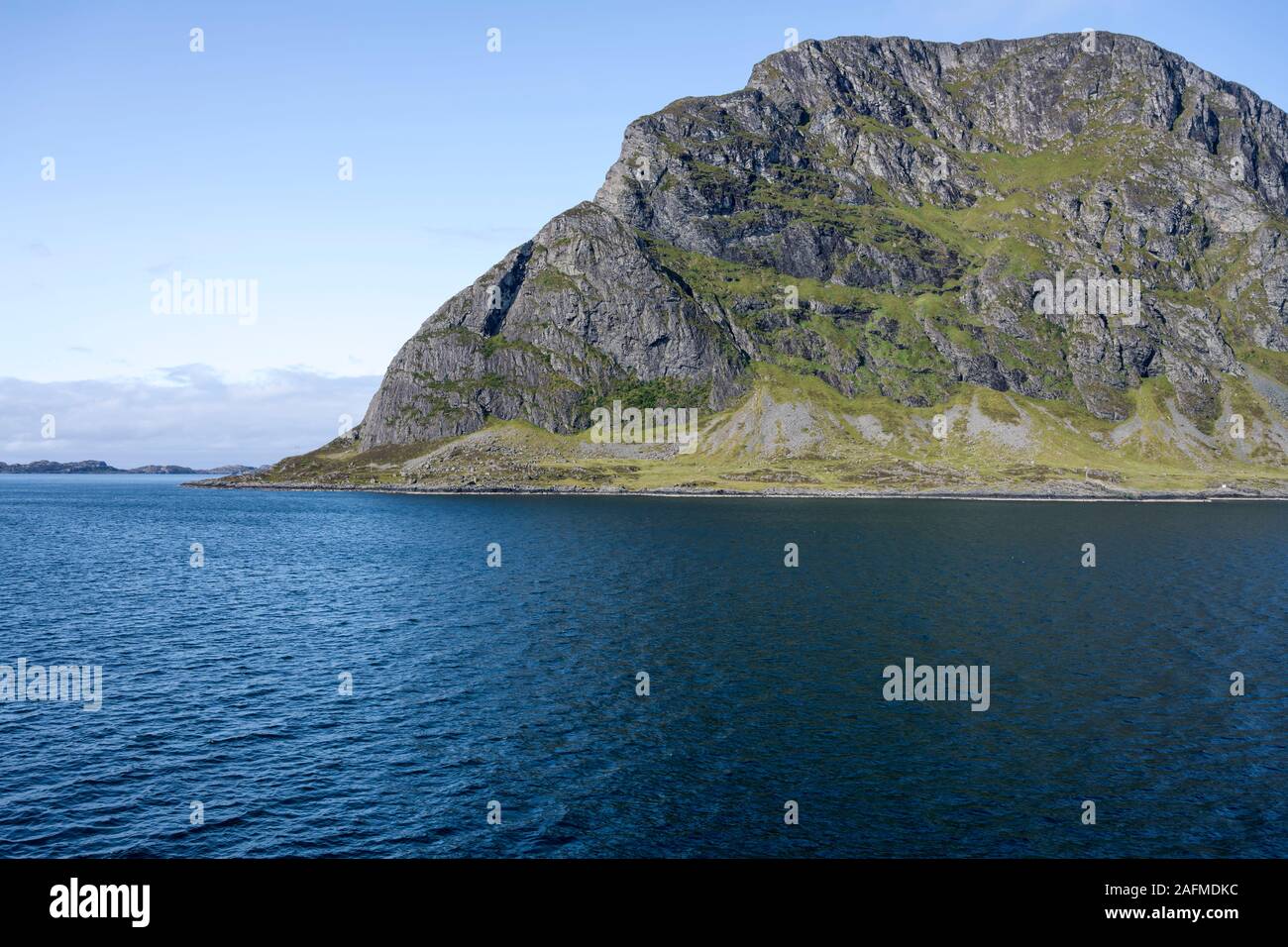 fjord landscape with island cape under steep green slopes of coast ...