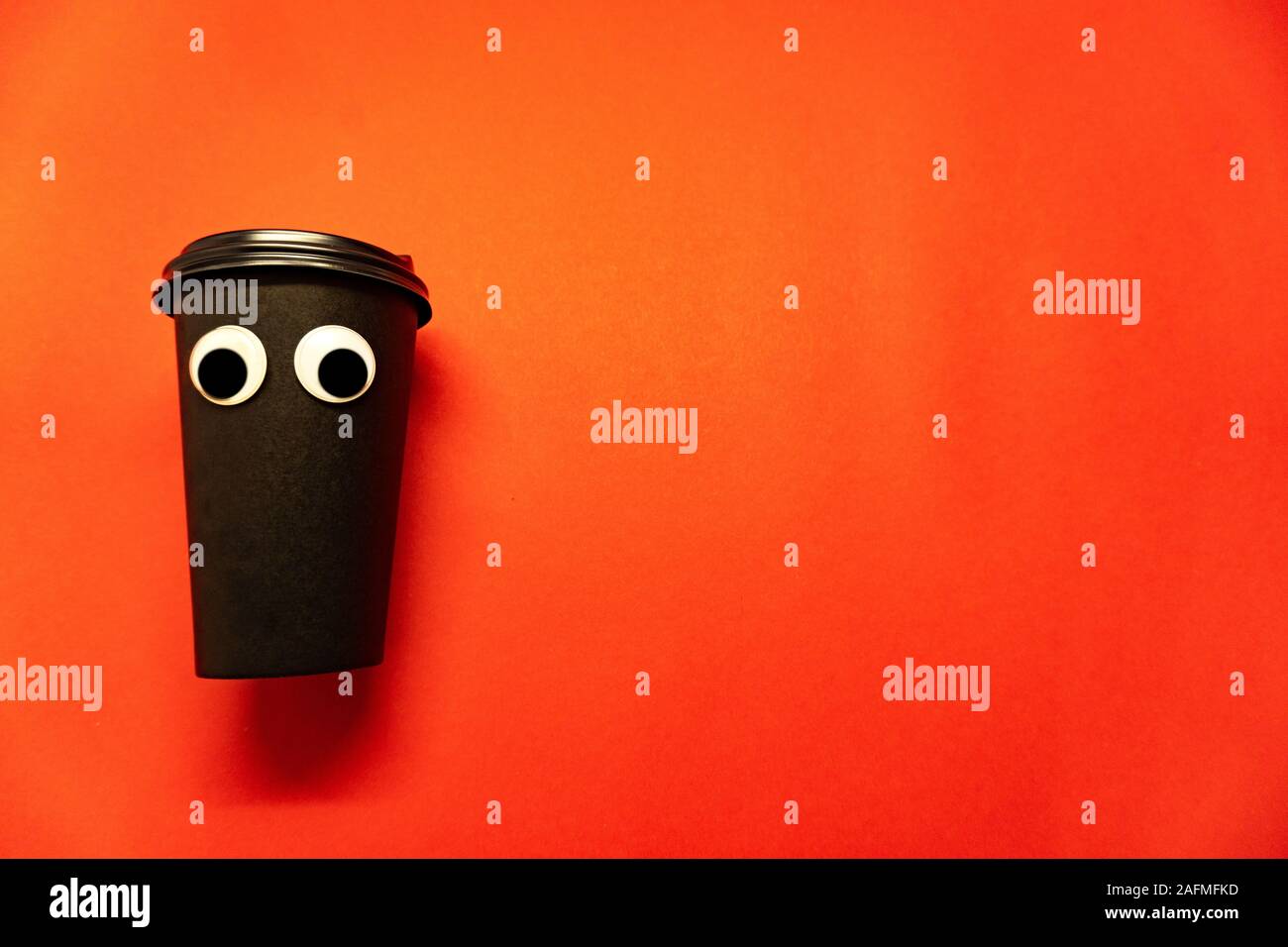 Coffee cup with googly eyes on red background Stock Photo - Alamy