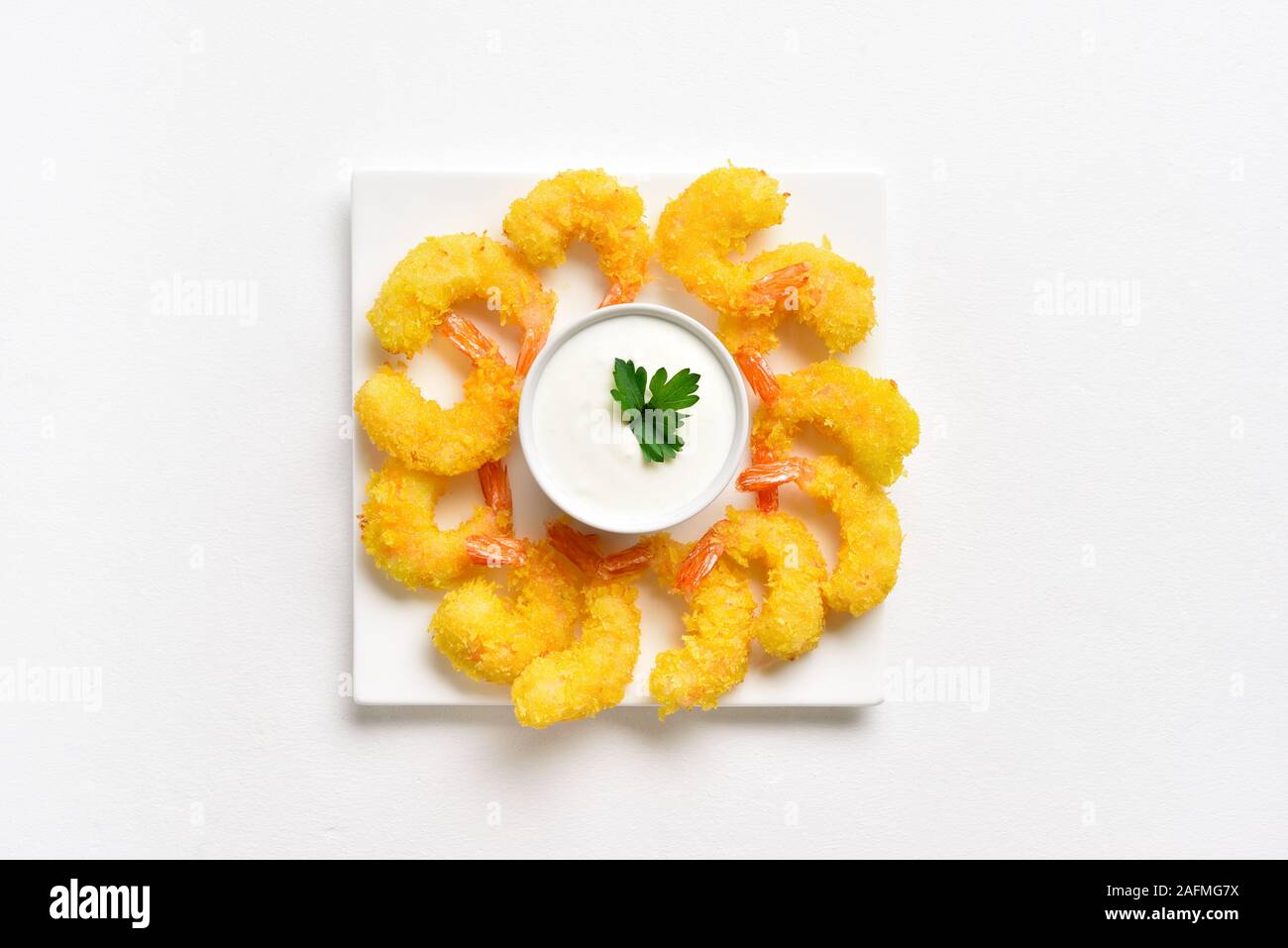 Deep fried breaded prawn with sauce on white plate over light stone ...
