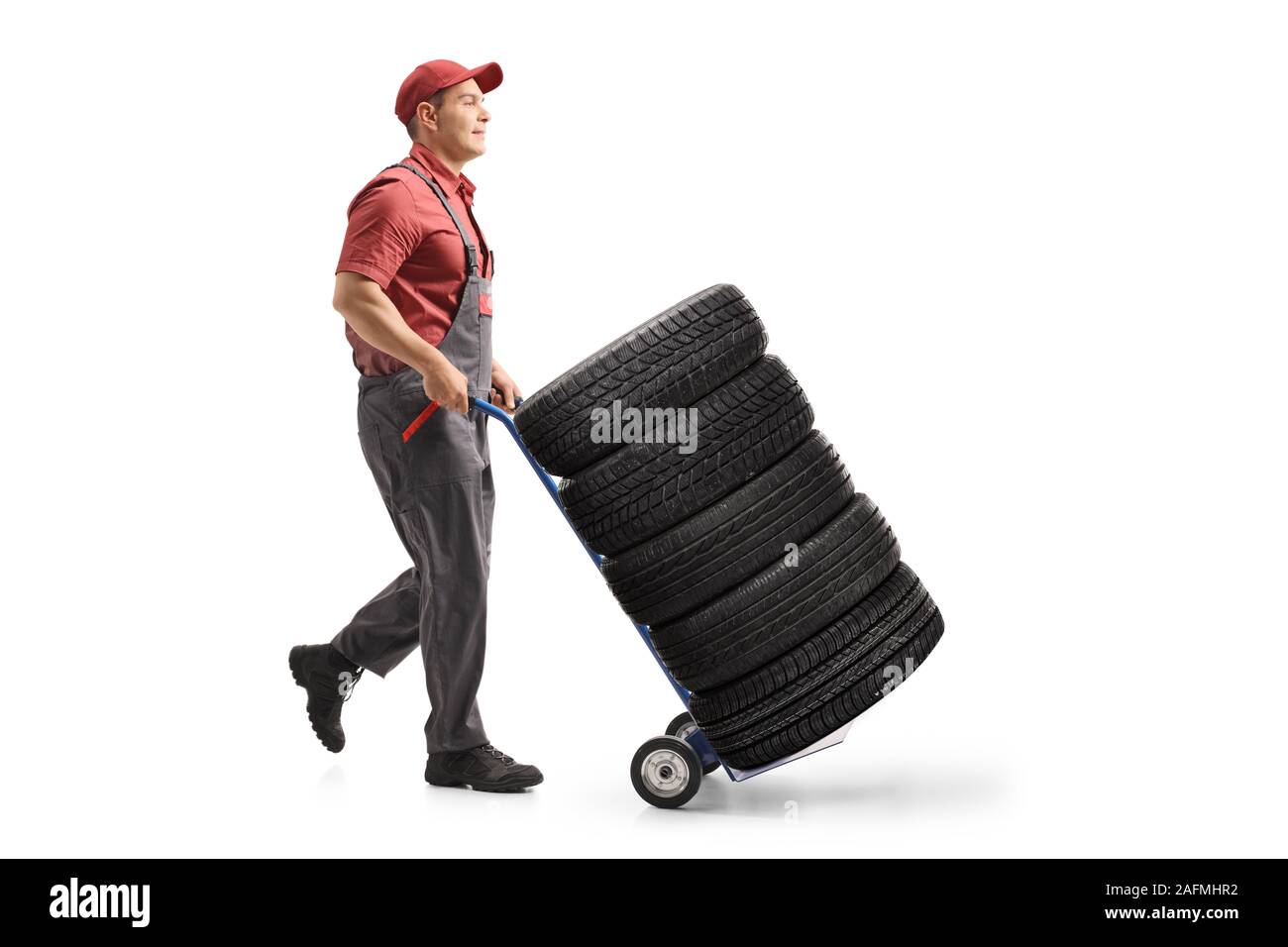 Full length profile shot of a worker pushing car tires with a hand ...