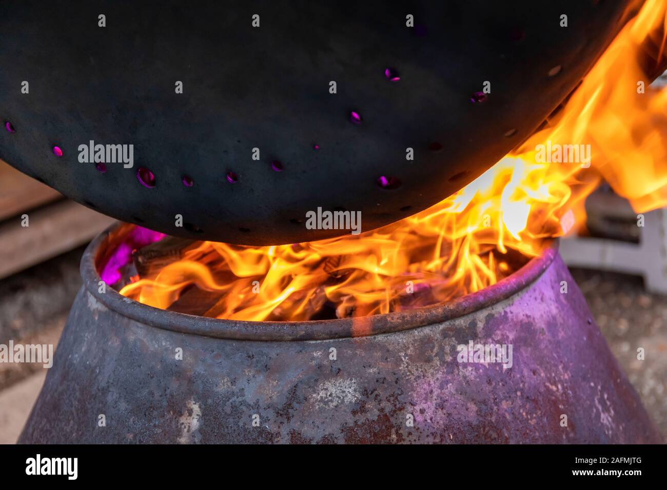 Flame of hot coal heats the perforated pot for cooking chestnuts. Close ...