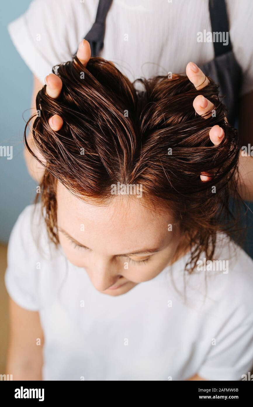 Hairdresser running fingers through client's hair to prepare it for ...