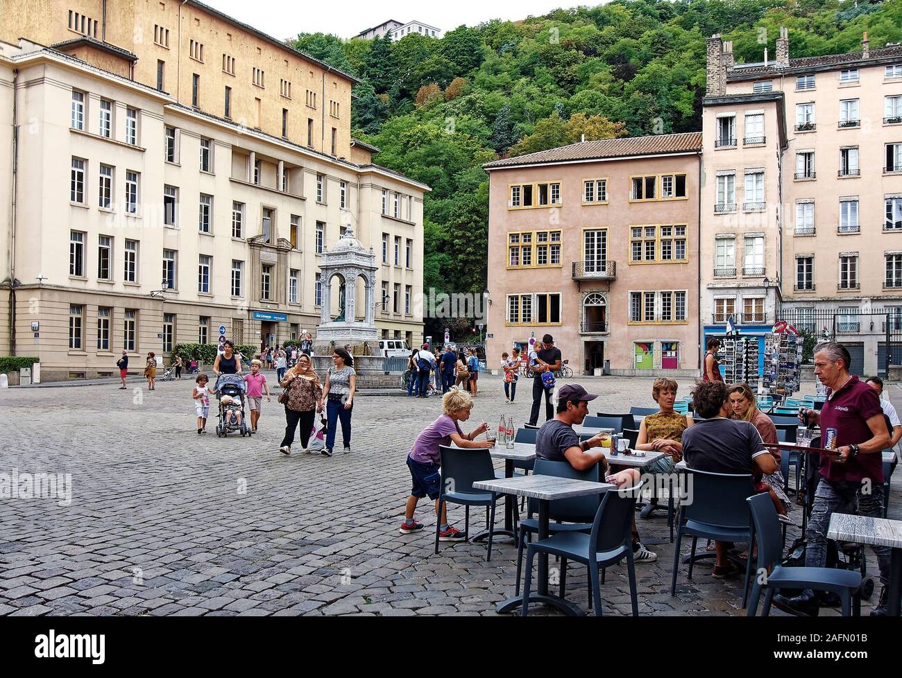 old cobblestone square, people, buildings, hillside, trees, street ...