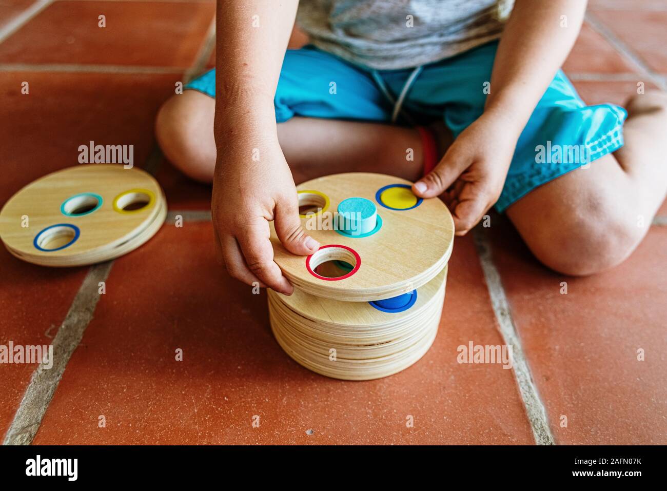Child having fun with an educational wooden game, to fit cylinders into ...