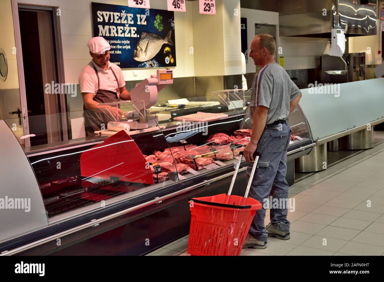 Man shopping at meat counter with shopping car inside supermarket ...
