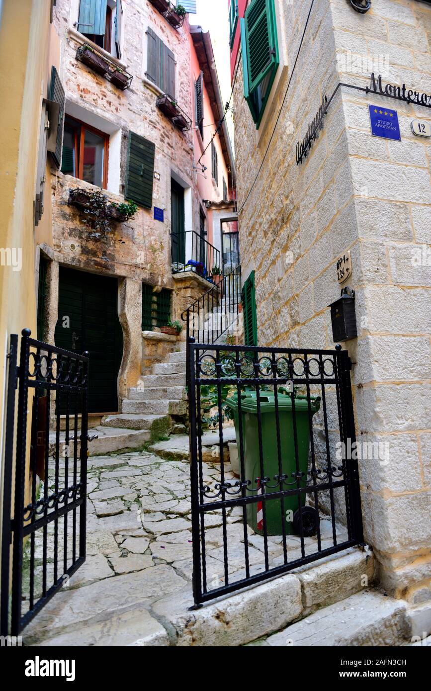 Open metal pedestrian gate leading to cobbled courtyard and stone steps ...