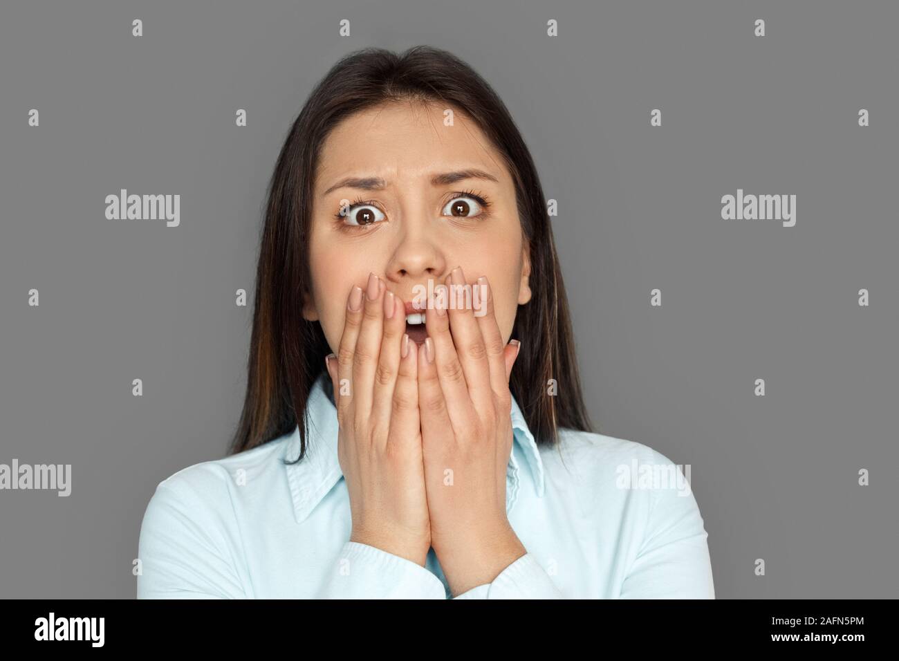 Freestyle. Young woman standing isolated on grey screaming frightened ...