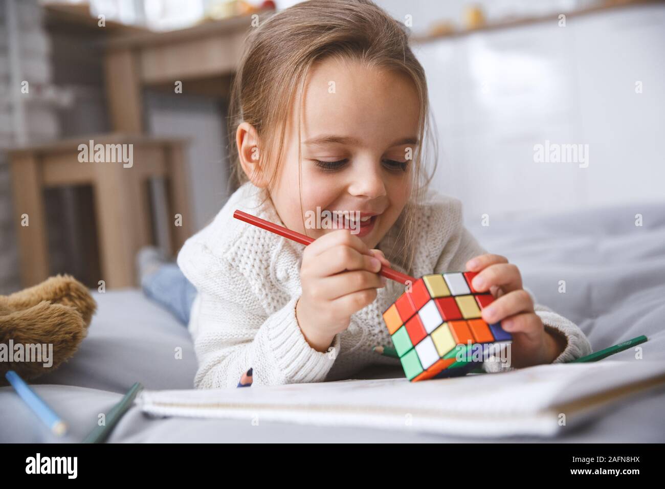 Little kid girl at home childhood concept playing with rubik's cube ...