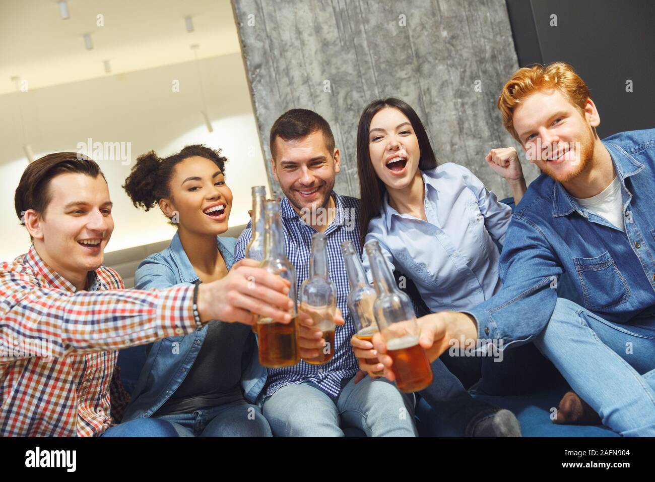 Group of friends having party indoors fun together sitting on coach ...