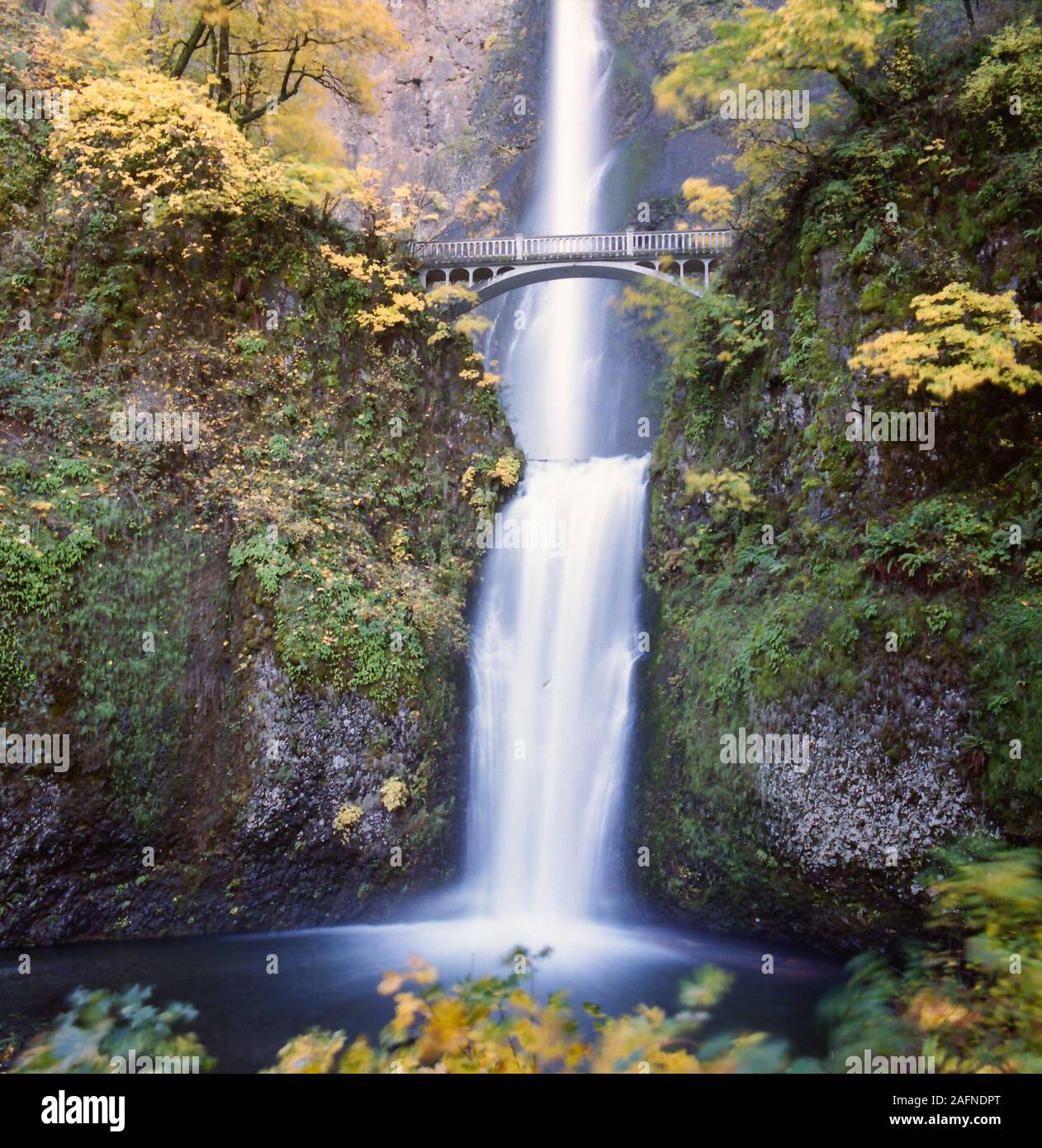 Beautiful scenery of a concrete bridge in front of a powerful waterfall ...