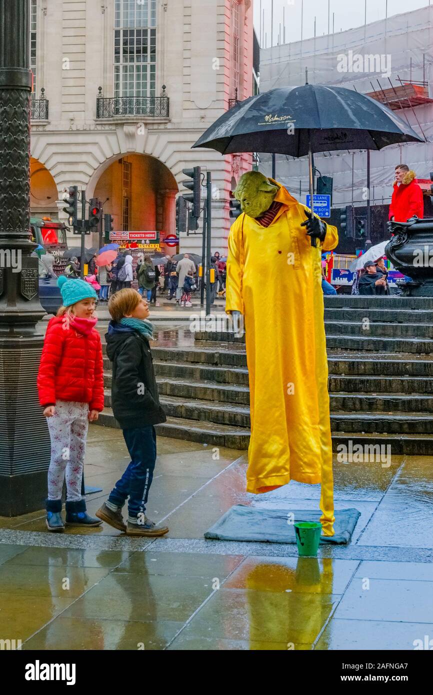 Street busker Yoda talks to kids, Rainy wet day, Piccadilly Circus ...