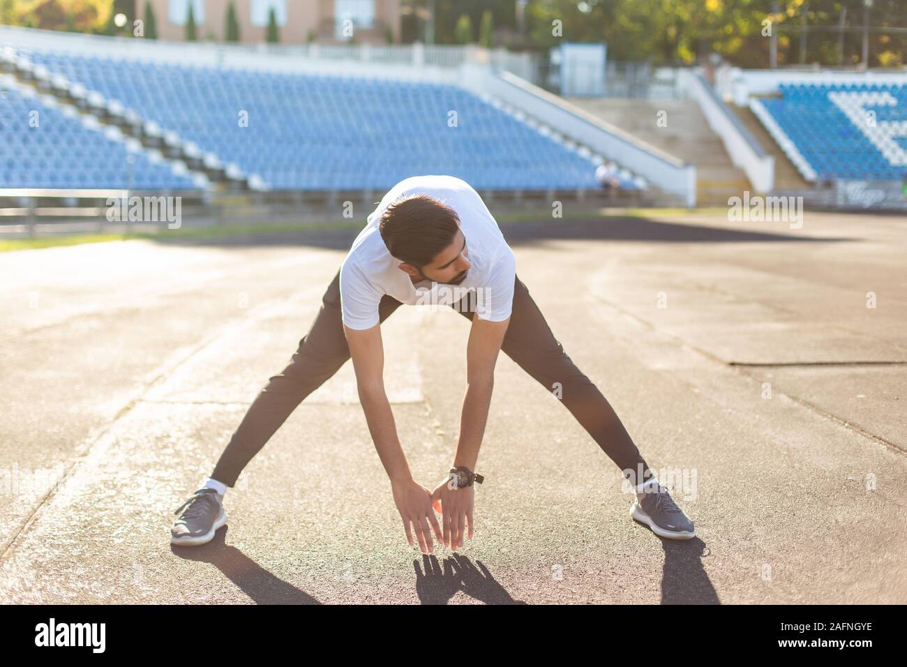 Athlete doing stretching exercise on running track Stock Photo - Alamy