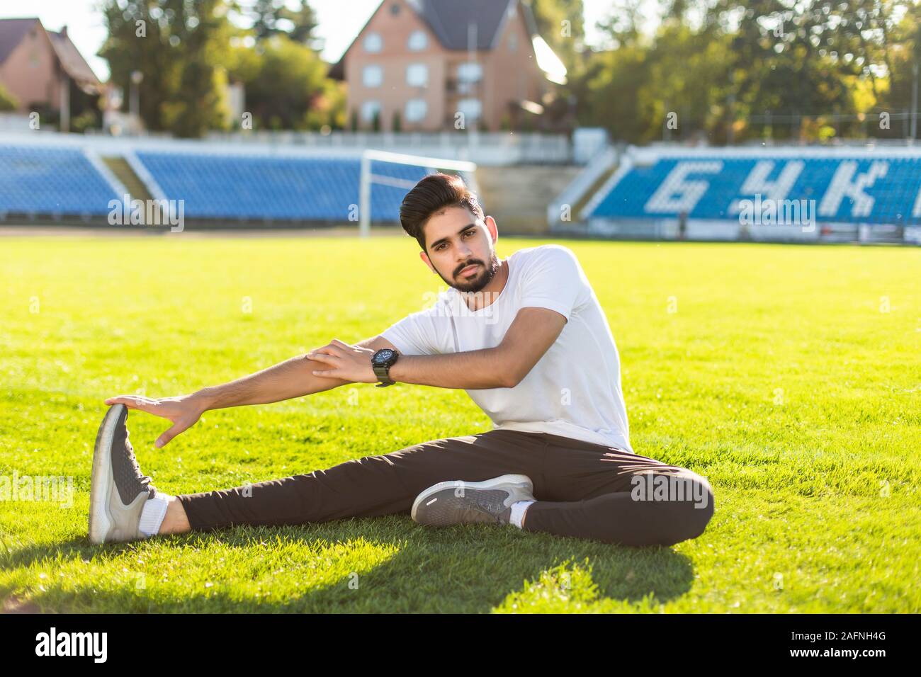 Fitness indian man stretching on the ground at stadium Stock Photo - Alamy