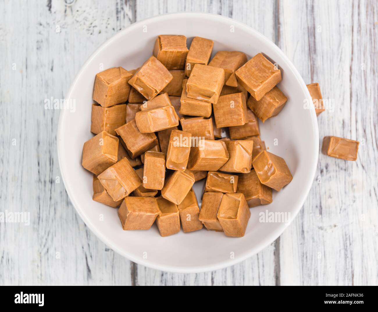 Caramel pieces as high detailed close-up shot on a vintage wooden table ...