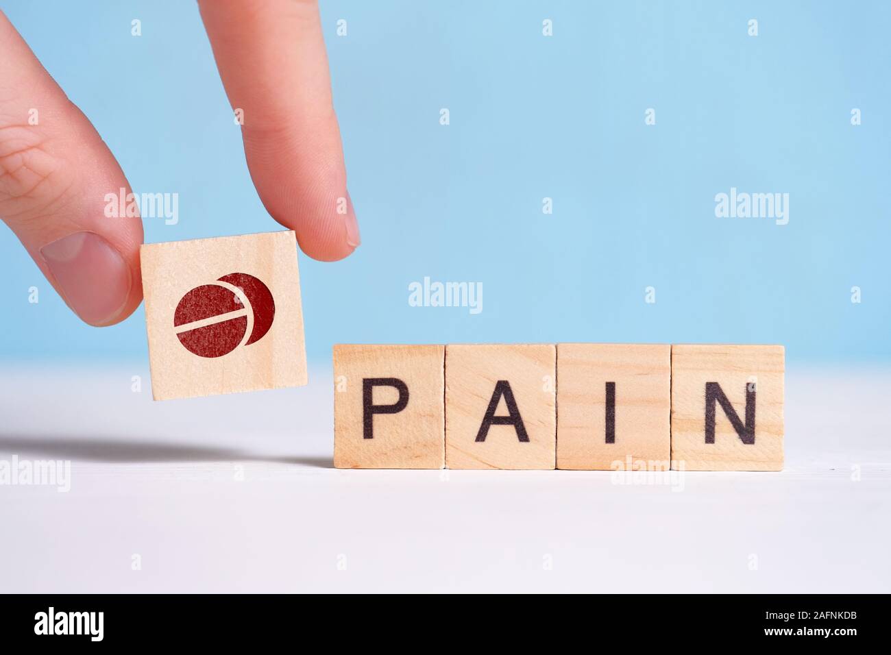 Concept application of pain pills. Fingers hold a cube with a drug icon ...