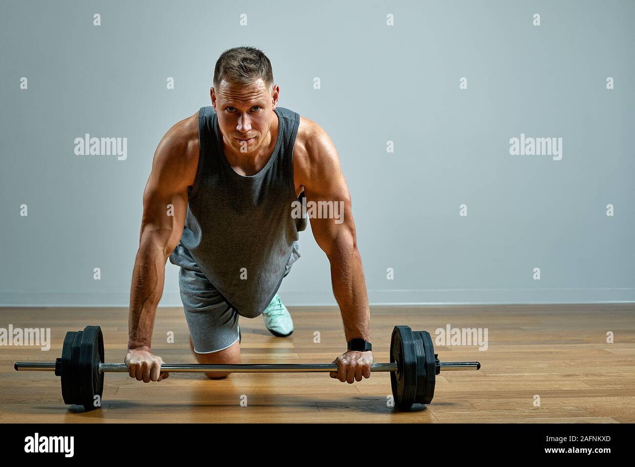 Man doing back workout, barbell row in studio over gray background ...