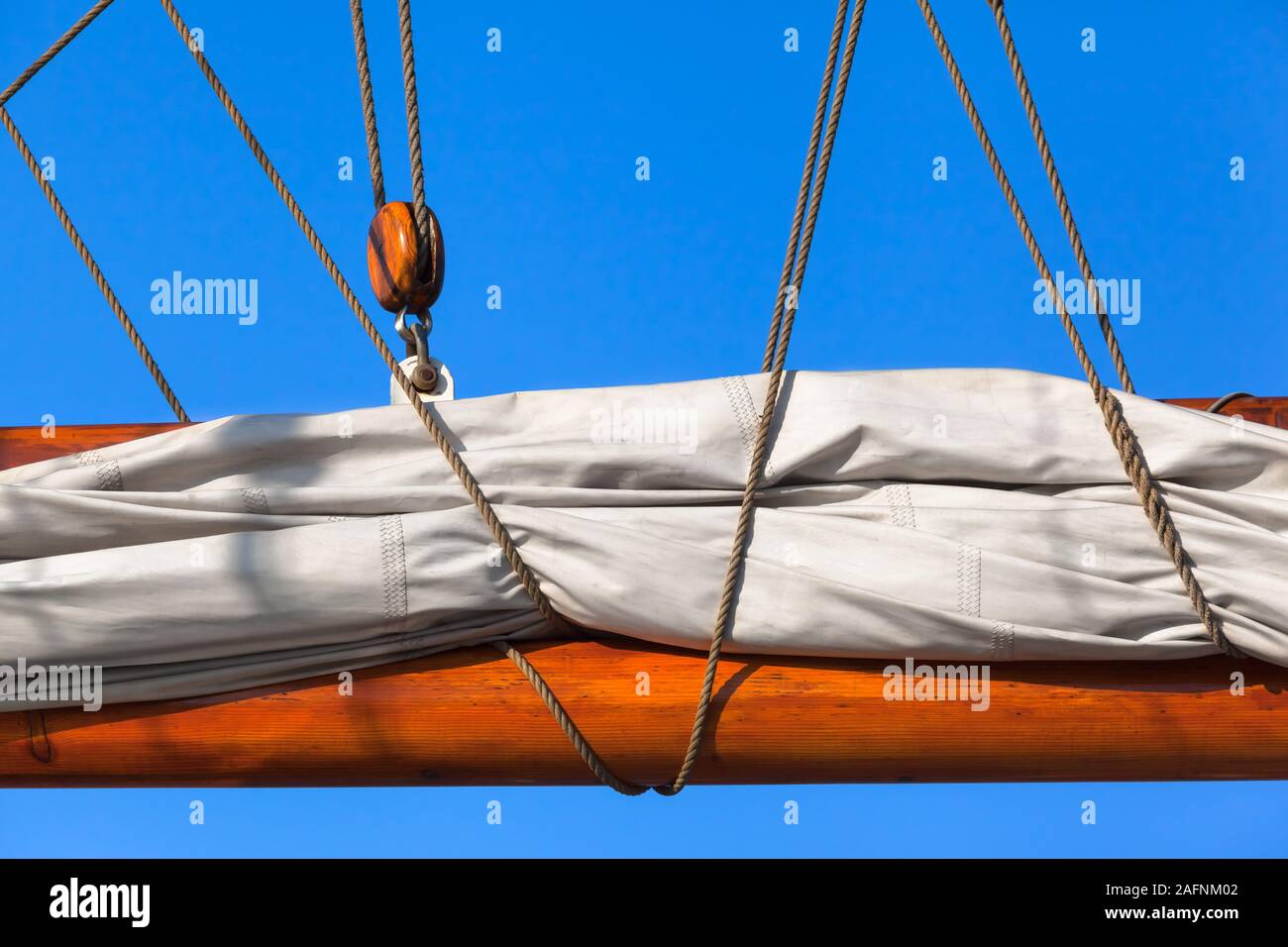 Detail of pulled in canvas sail at wooden sailship with ropes and ...