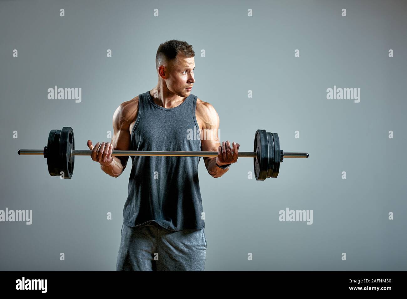 Man doing back workout, barbell row in studio over gray background ...