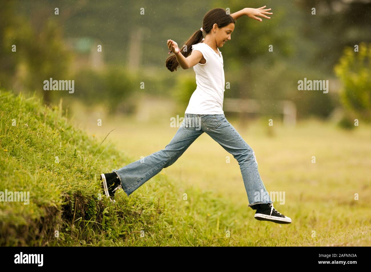 Girl taking leap on grassy area Stock Photo - Alamy