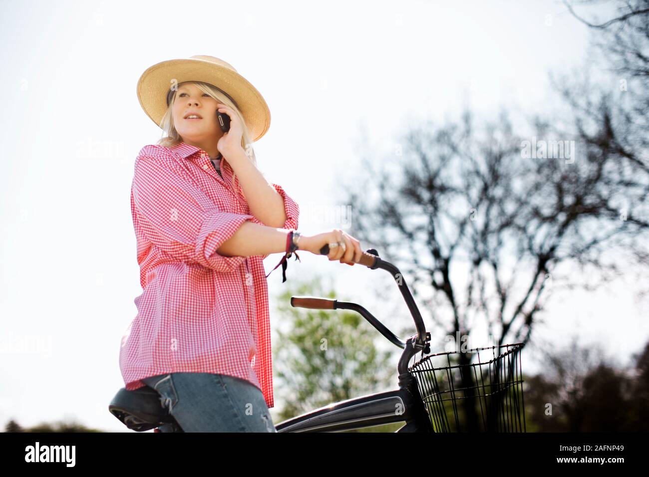 Teenage girl riding her bicycle and talking on her mobile phone Stock ...