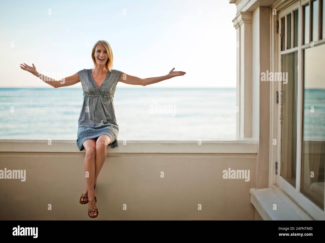 Mid adult woman sitting on the window sill of her hotel room Stock ...