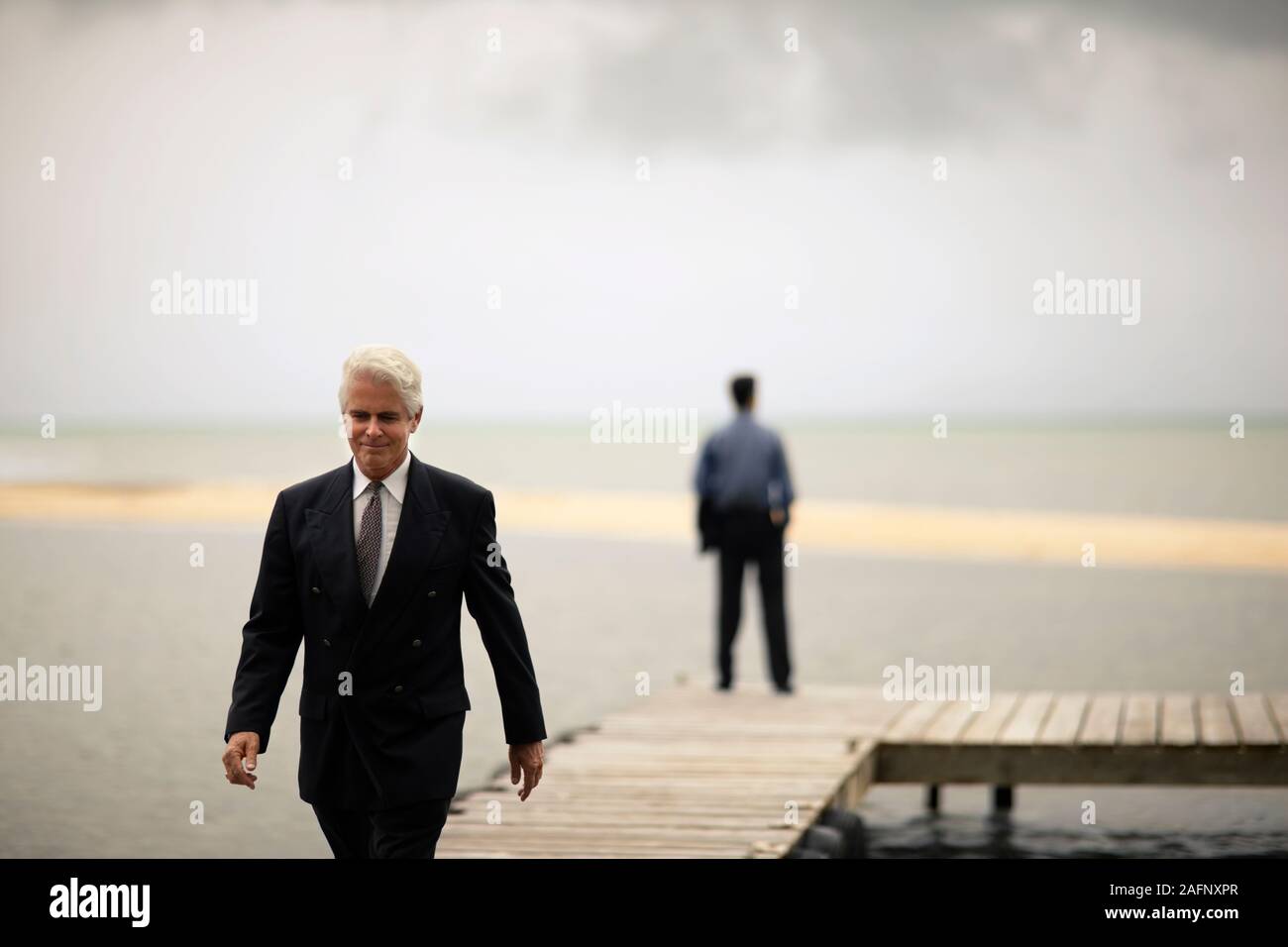 Mature businessman walking away from a colleague along a jetty Stock ...