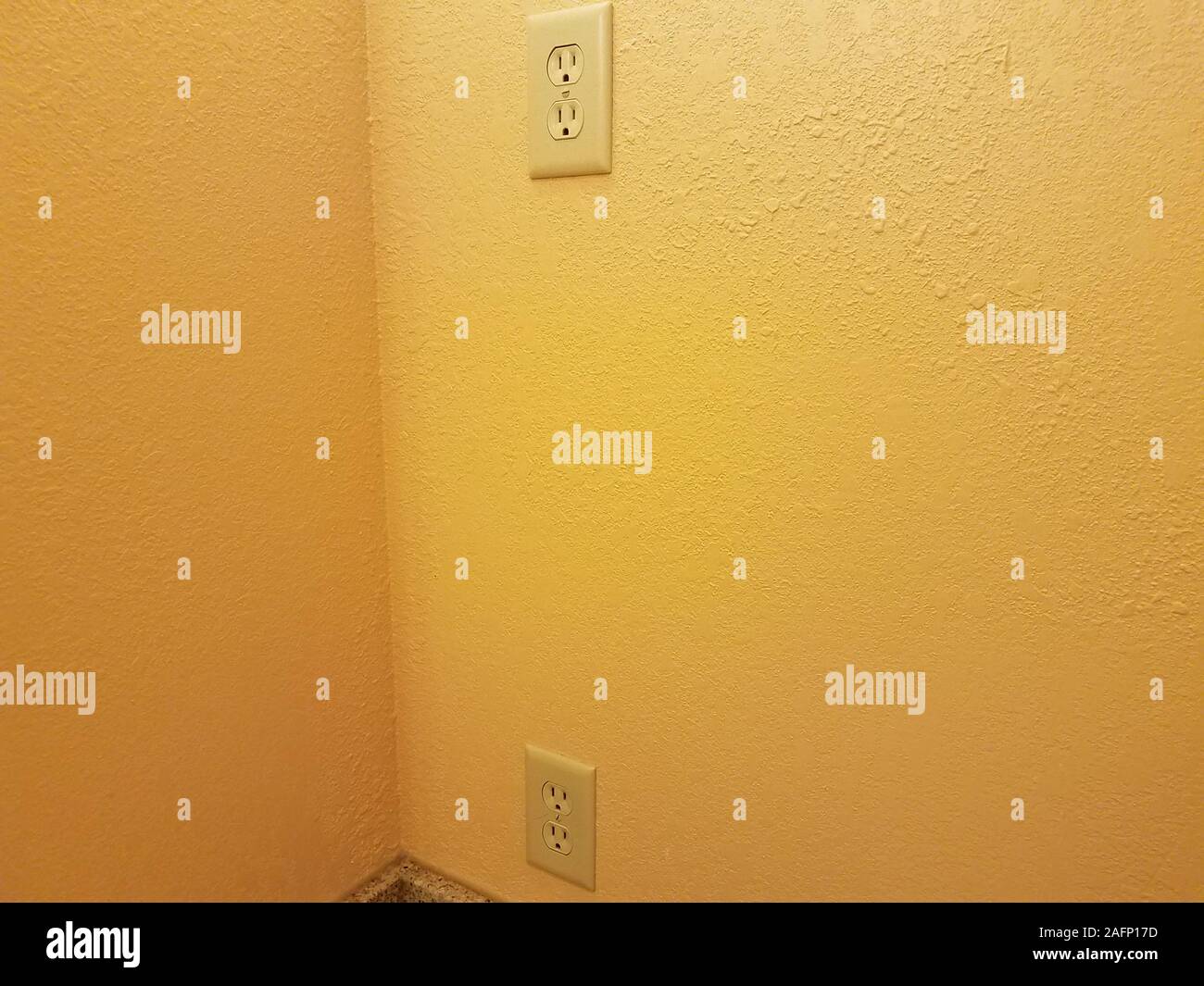 electrical outlets on orange or yellow painted wall in corner Stock ...