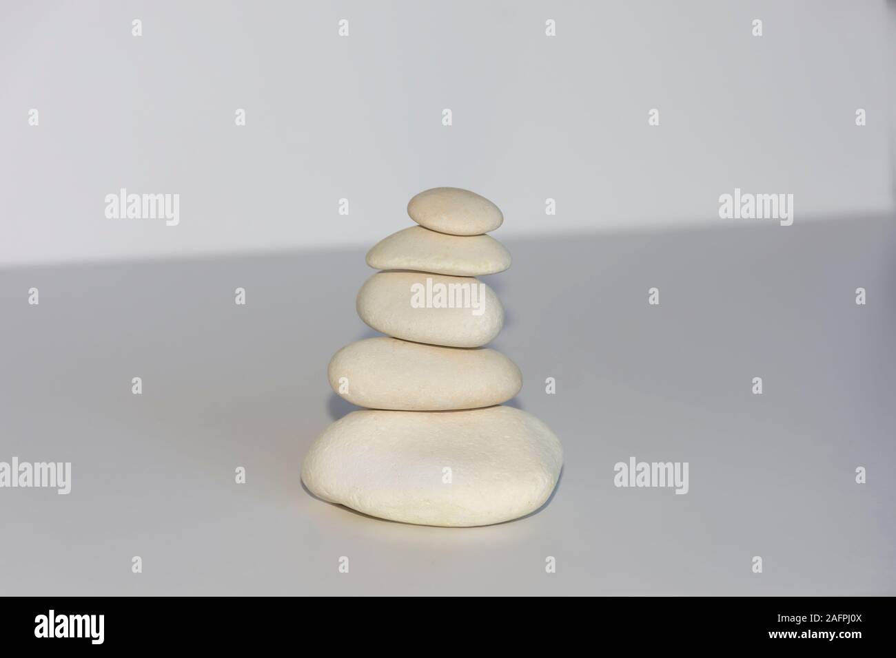 White stone in balance on white background. Meditation, peace, balanced ...