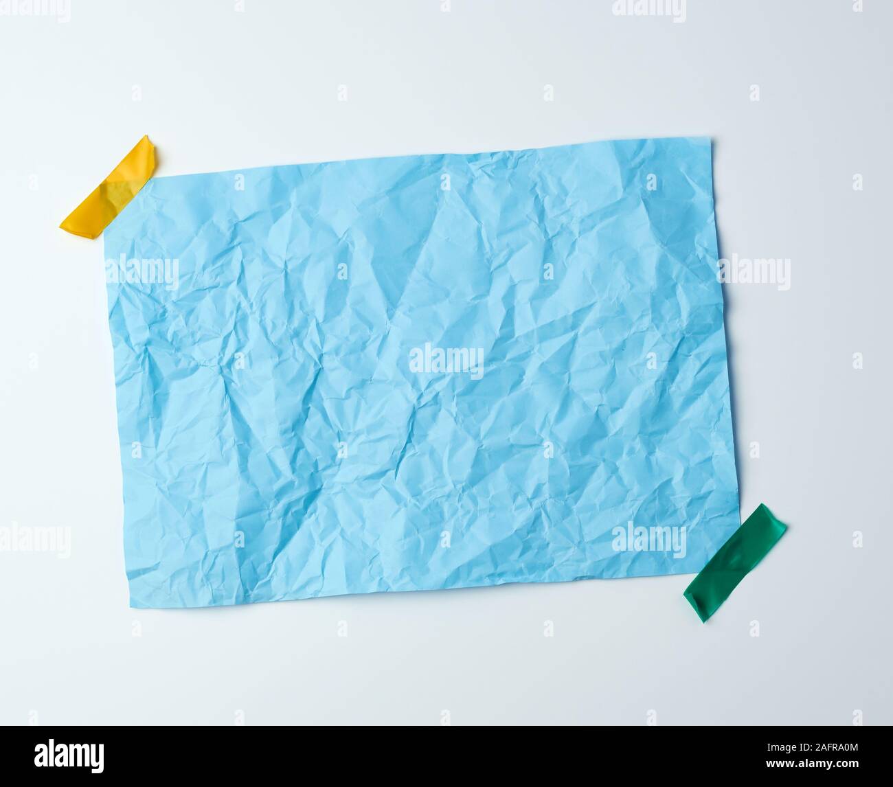 blue crumpled sheet of paper glued with adhesive tape on a white ...