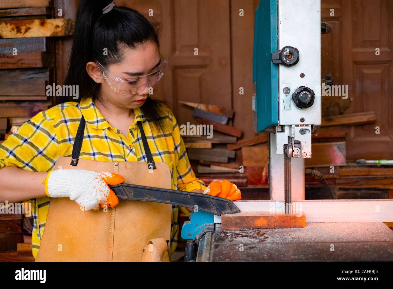 Women standing is craft working cut wood at a work bench with band saws ...