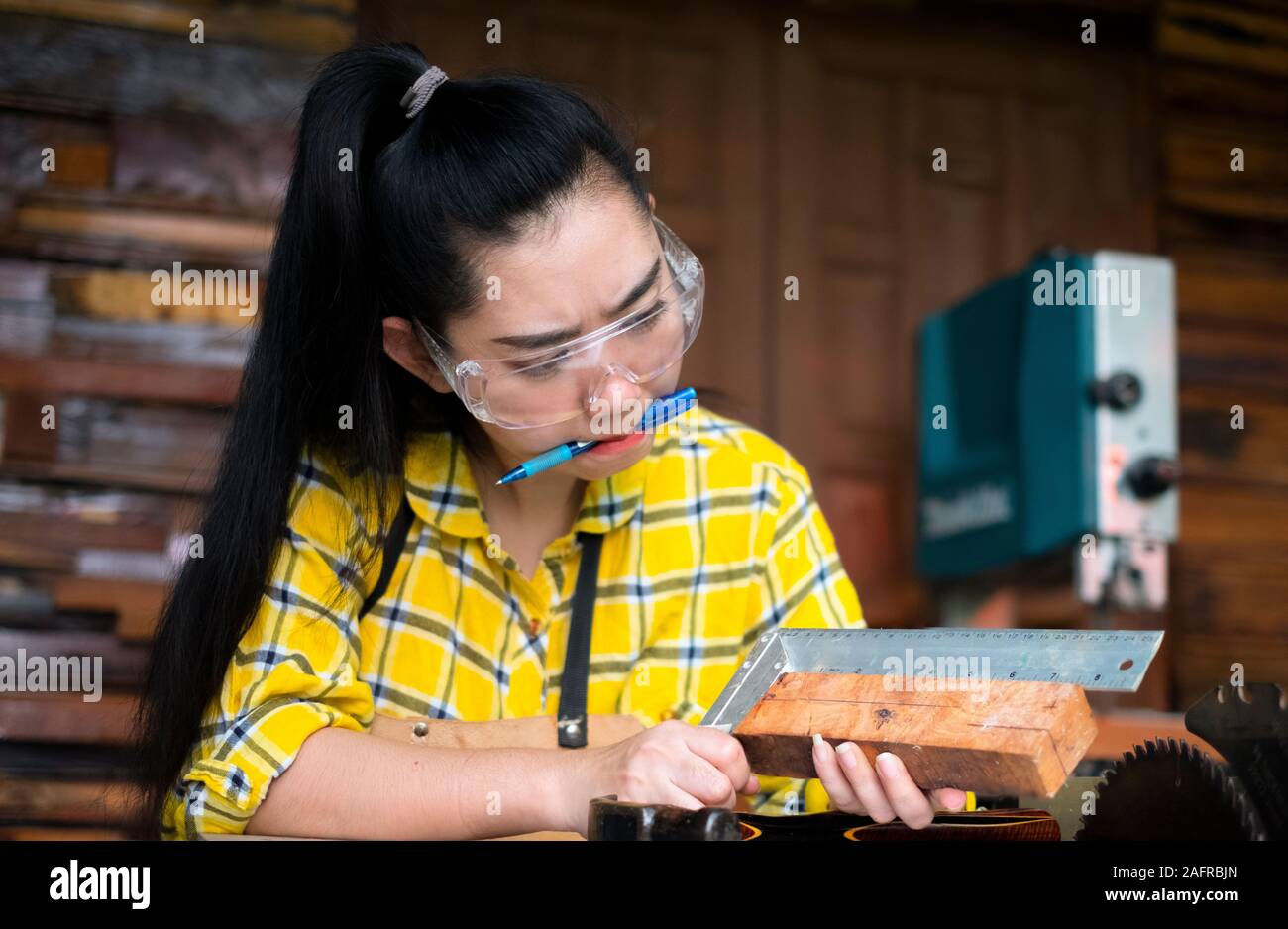 Woman holding ruler and pencil while making marks on the wood at the ...