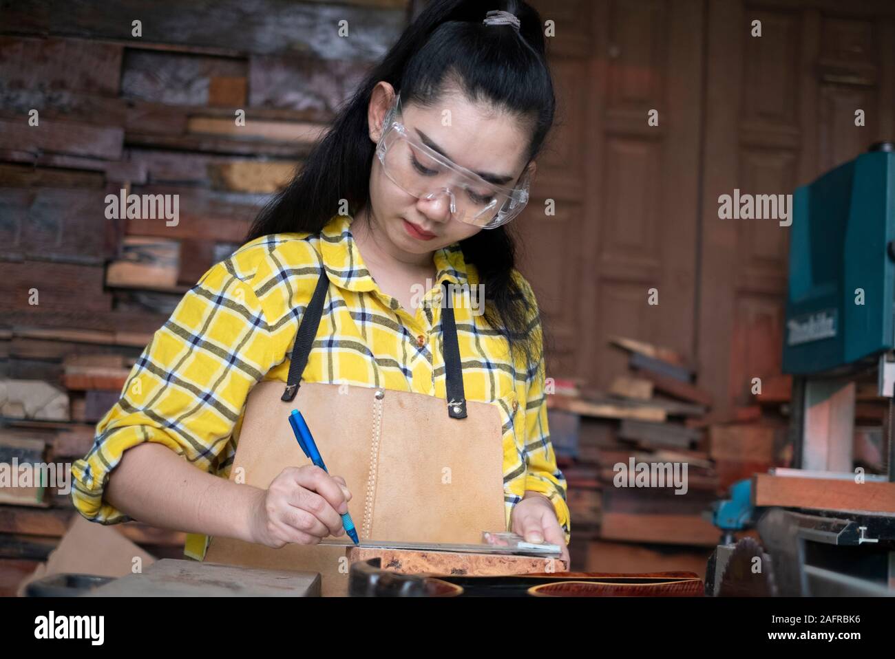 Woman holding ruler and pencil while making marks on the wood at the ...