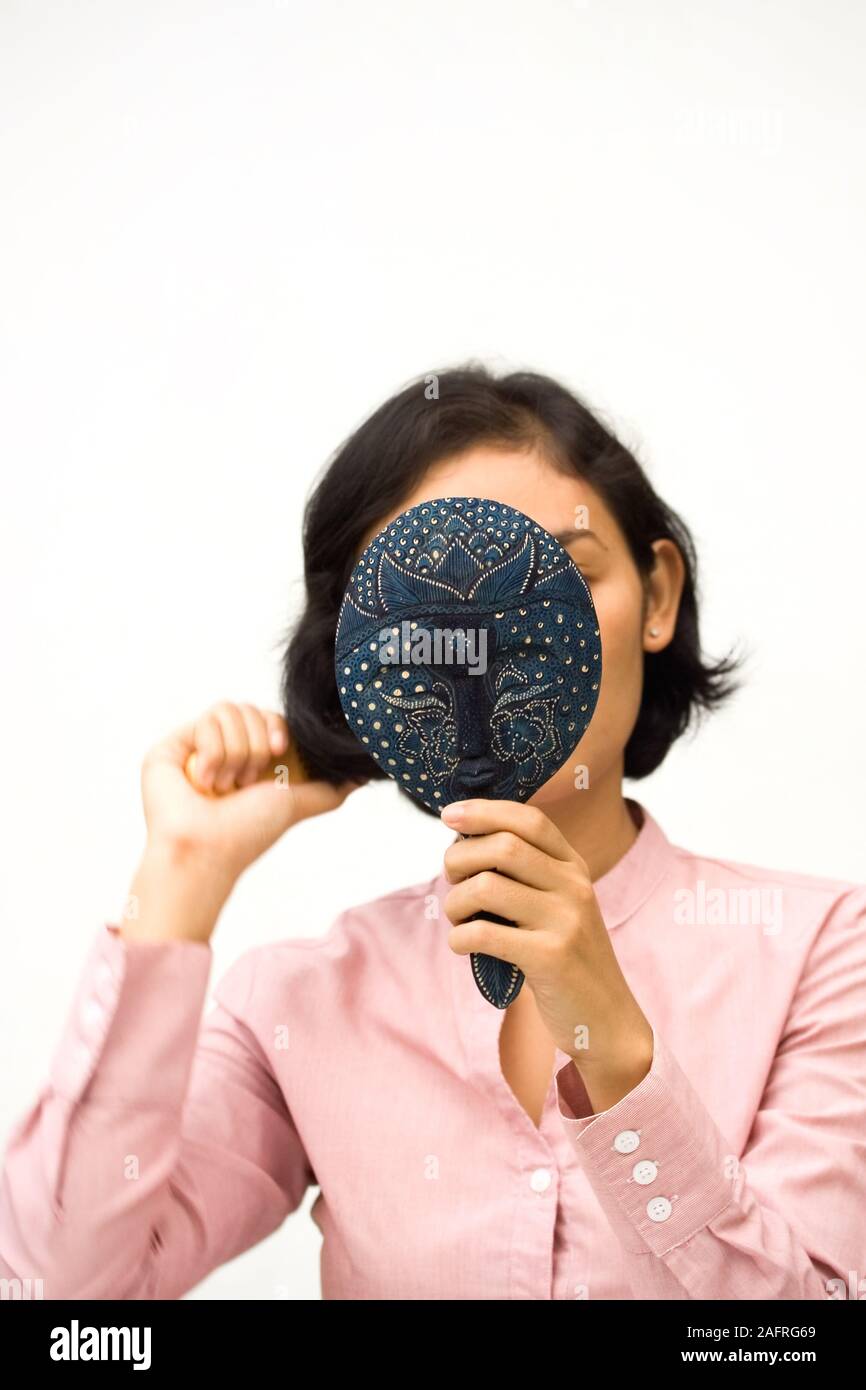 Southeast Asian young woman grooming with hairbrush and mirror on hands ...