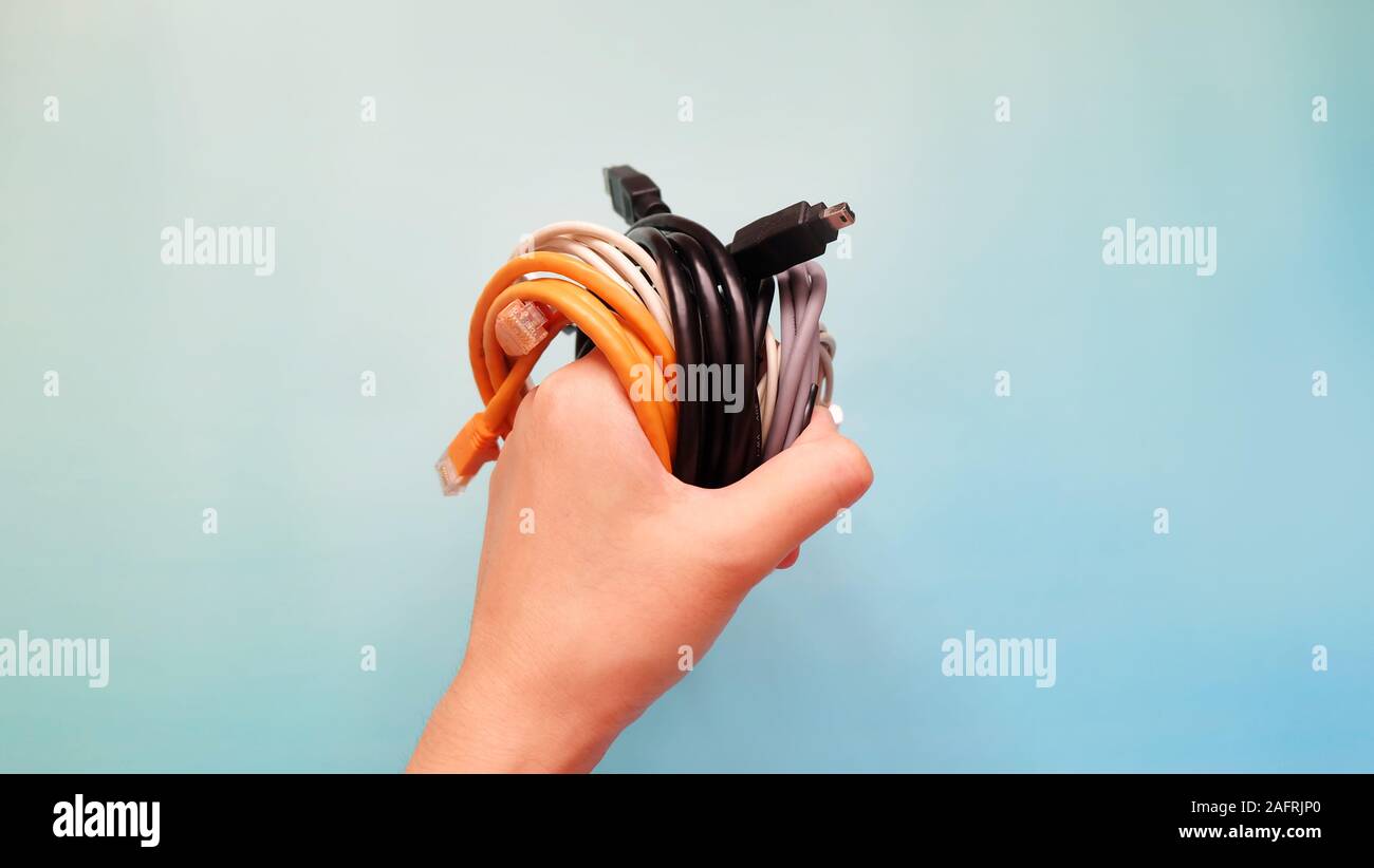 A hand holding cables in different colors, rolled up neatly, in the ...