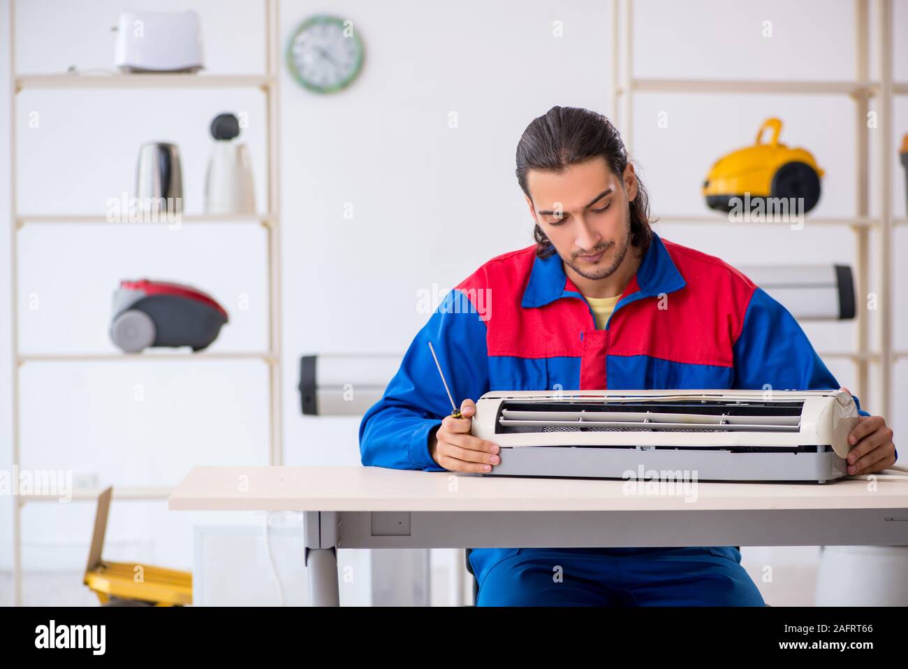The young male contractor repairing air-conditioner at workshop Stock ...
