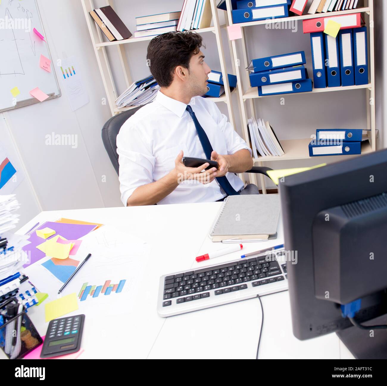 Businessman working in the office with piles of books and papers doing ...
