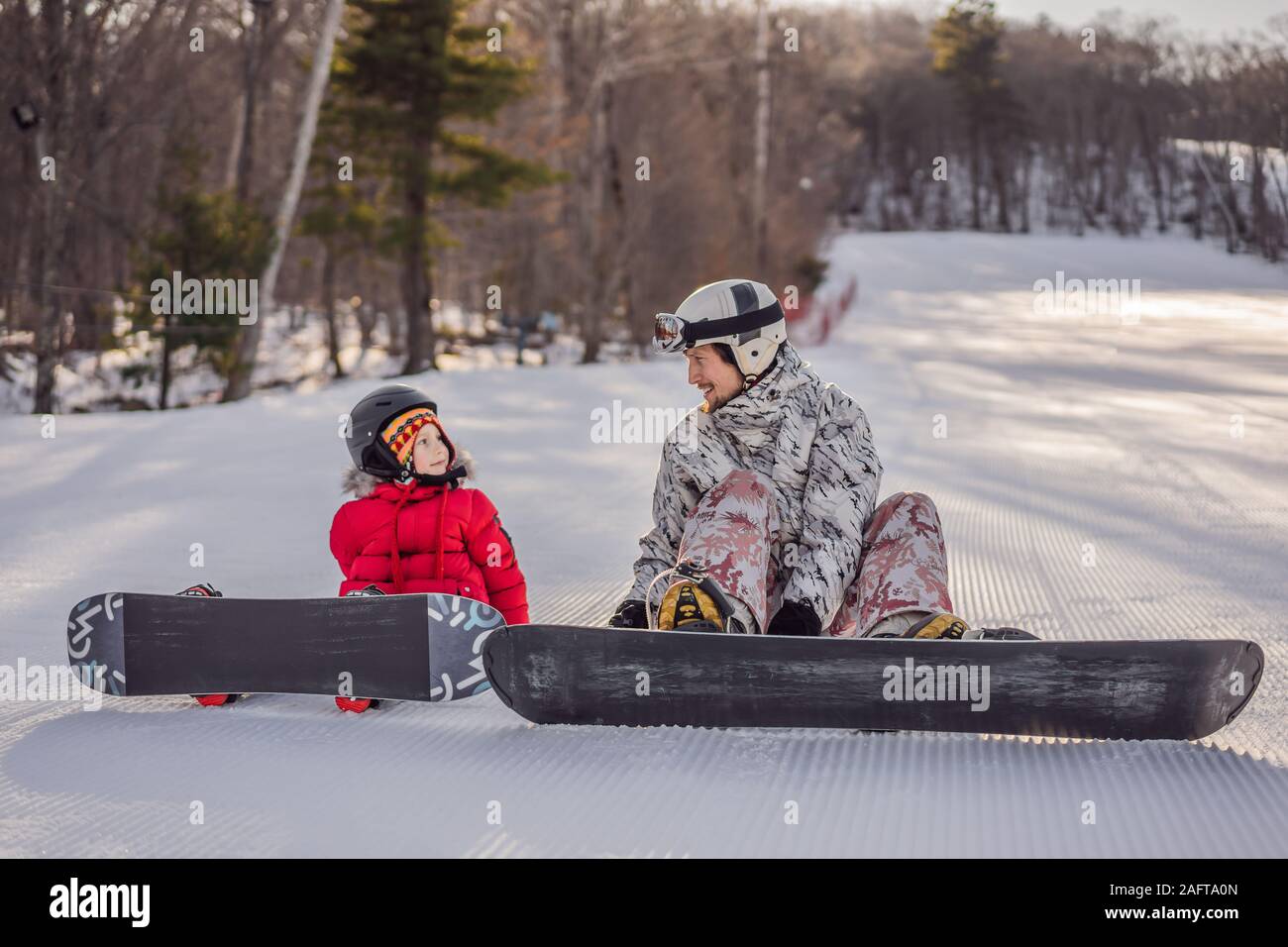 Dad teaches son snowboarding. Activities for children in winter ...
