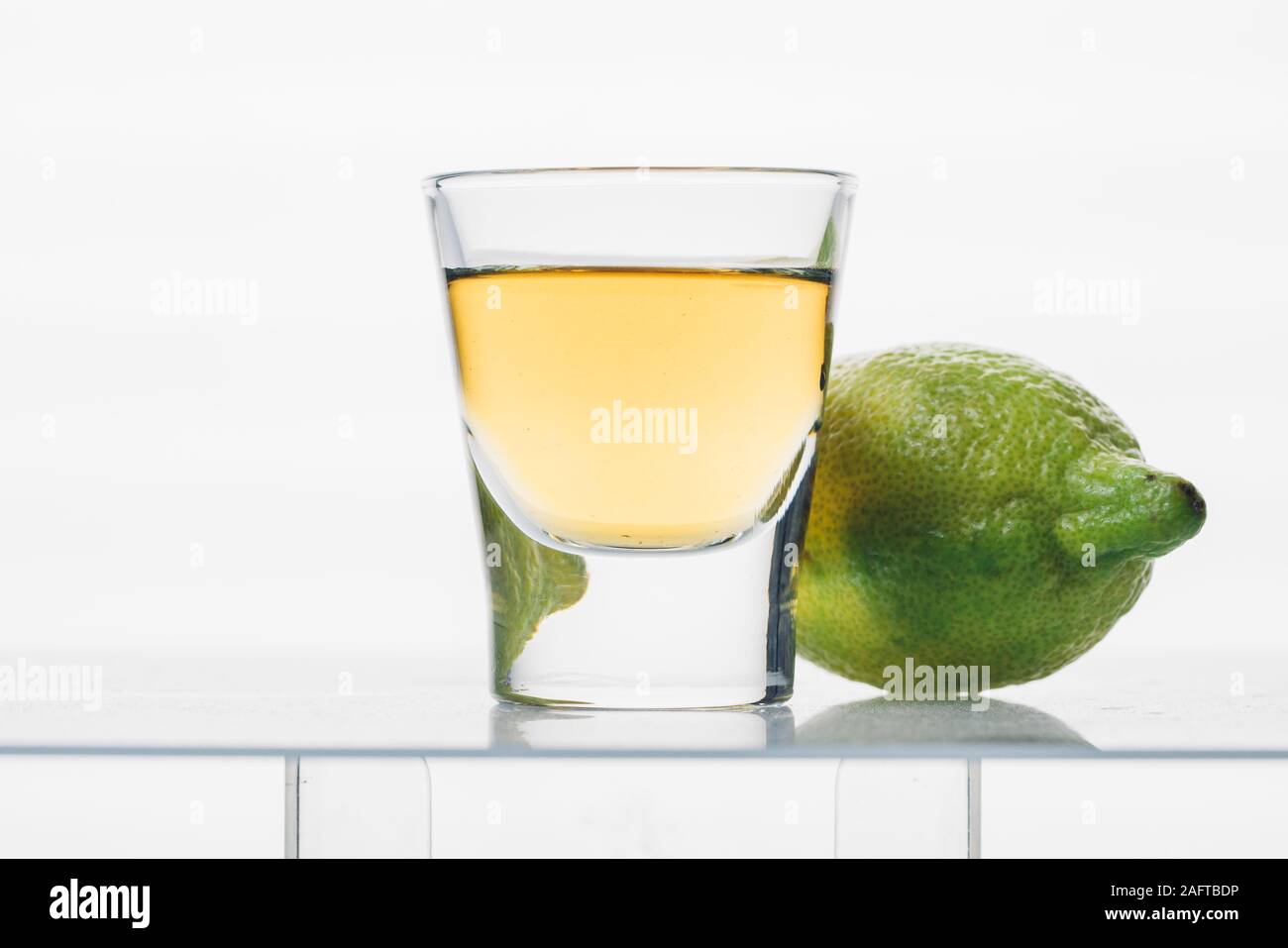 glass with strong alcoholic drink and lemon on a white background Stock ...
