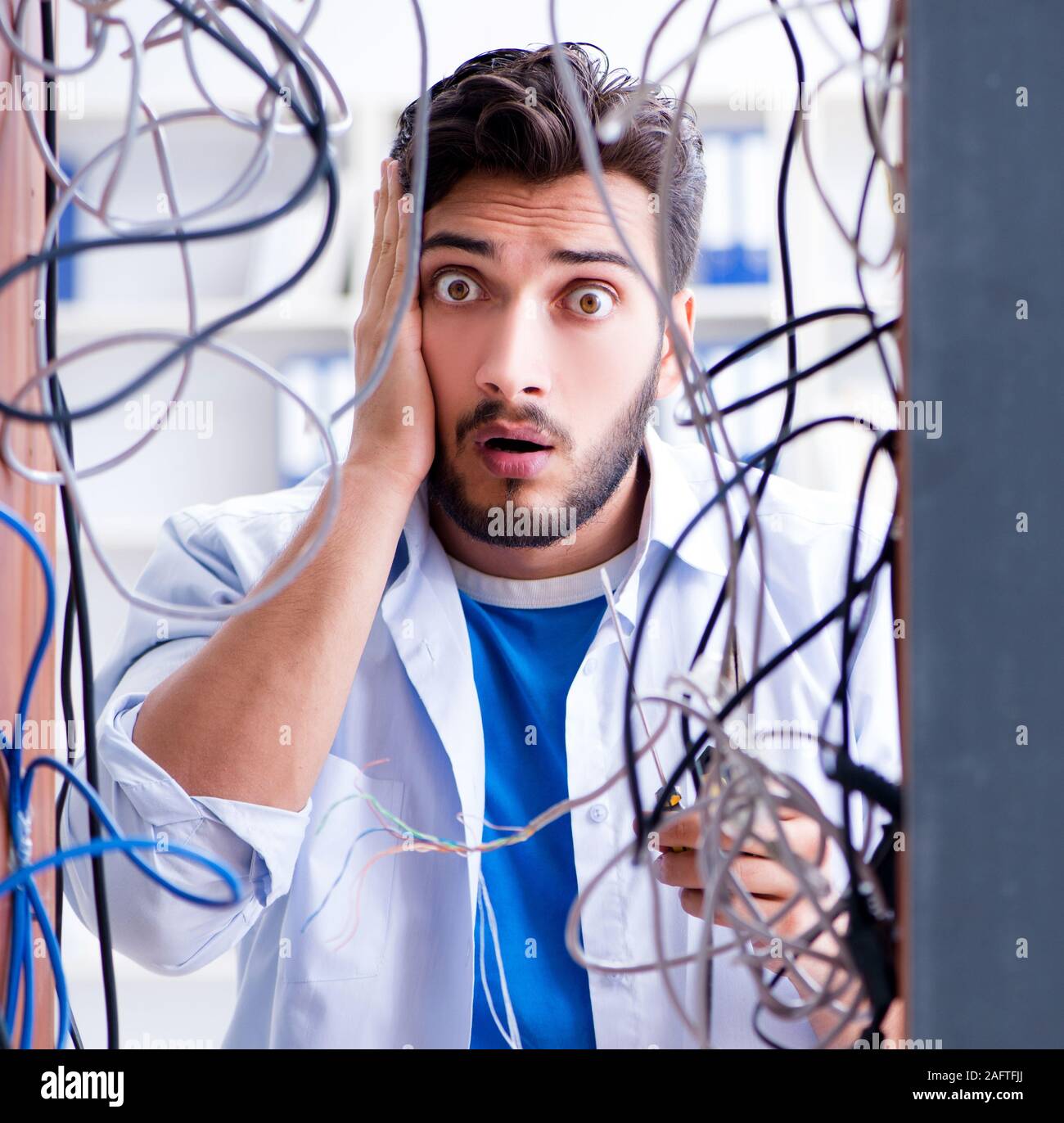 The electrician trying to untangle wires in repair concept Stock Photo ...