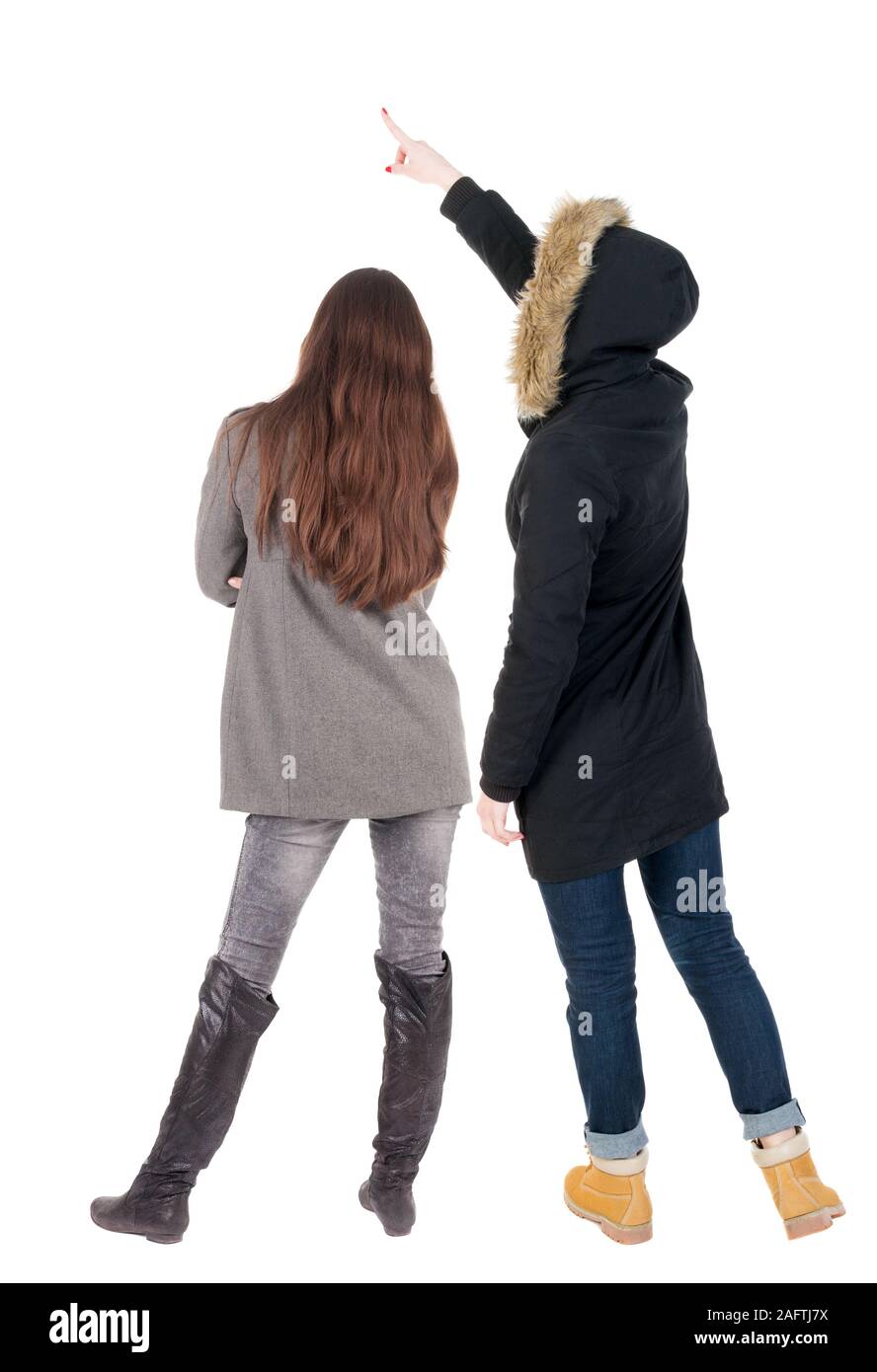 Back view of two pointing young girl in winter jacket. Rear view people ...